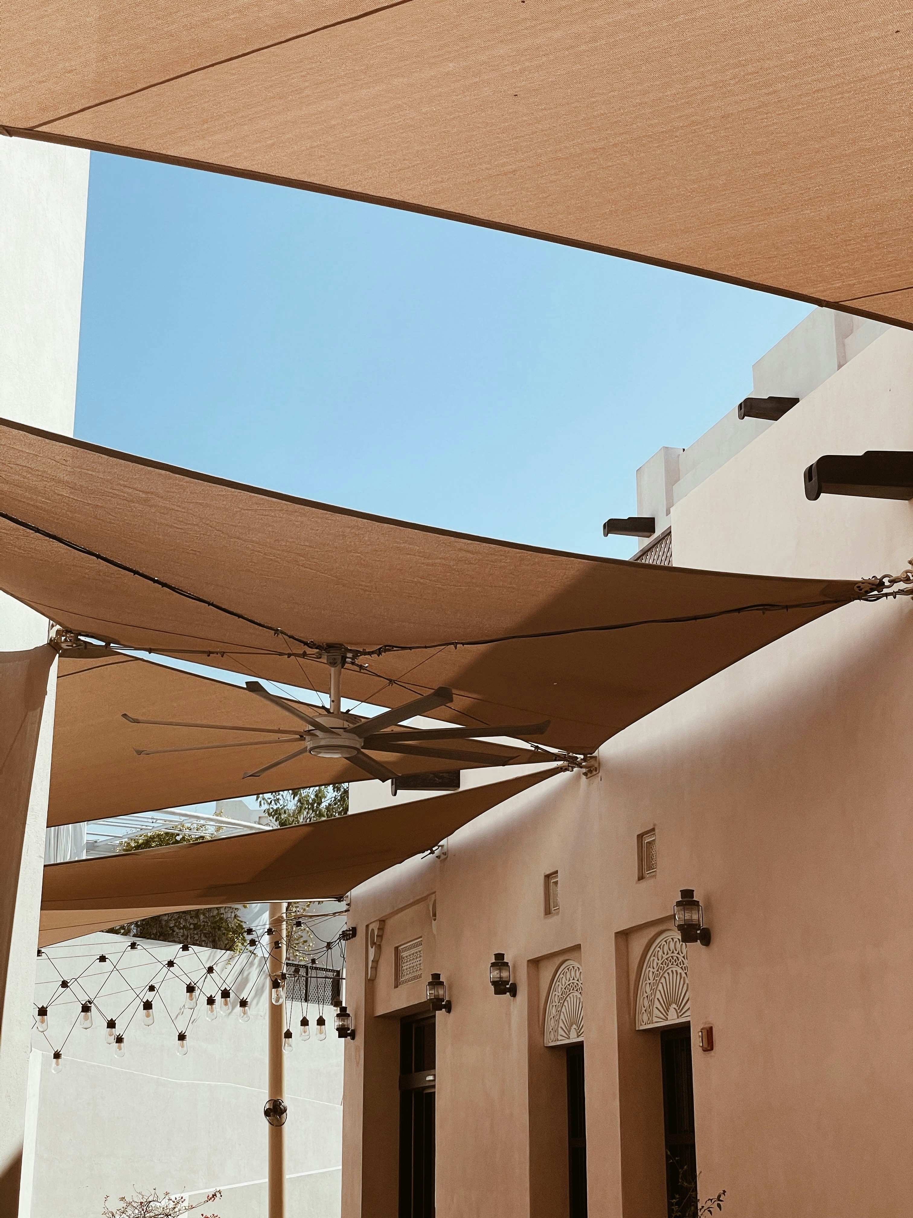 Shade sails and sunlit arches: a courtyard in warm light