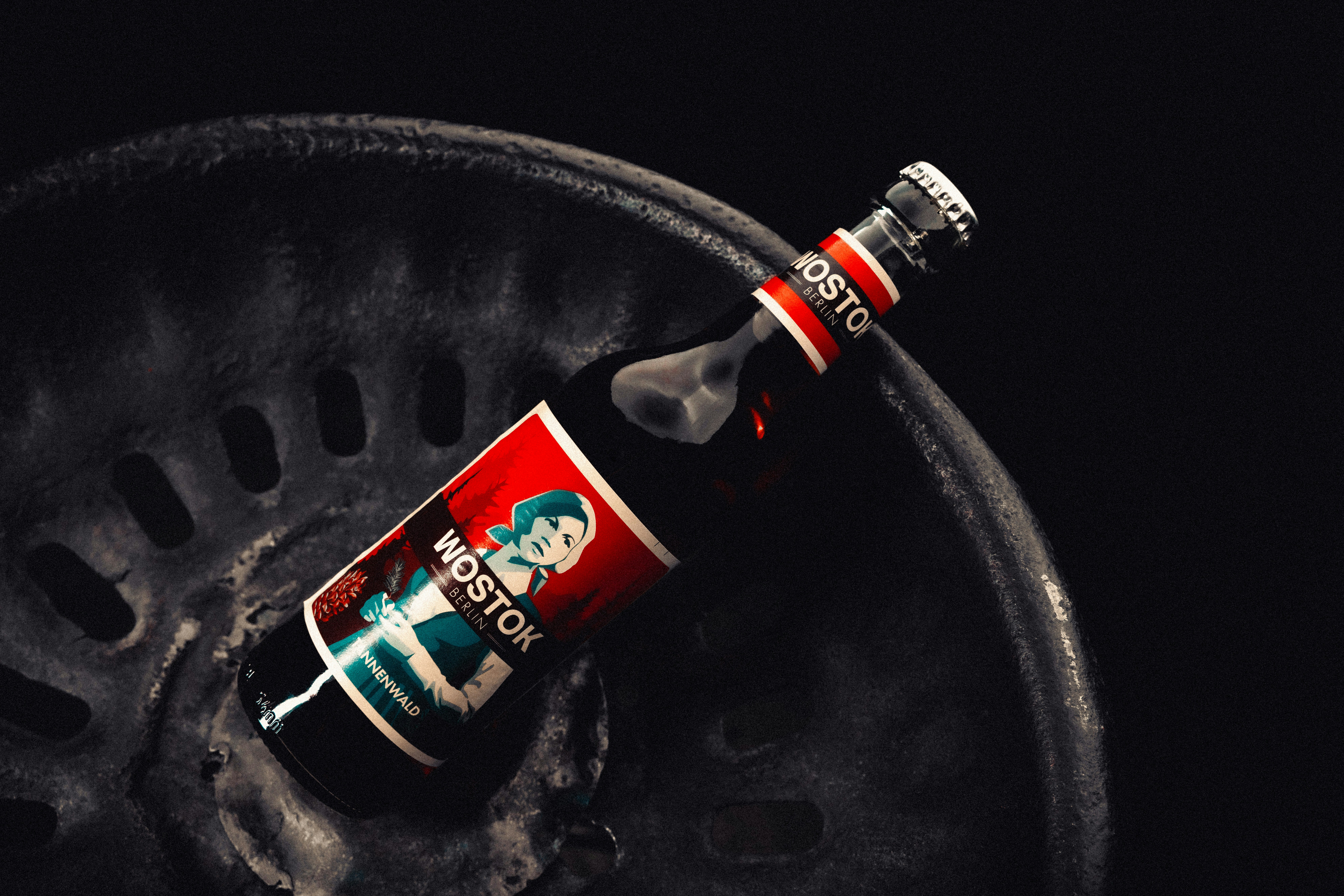 Red Label in the Dark: A Bottle Resting on a Weathered Wheel