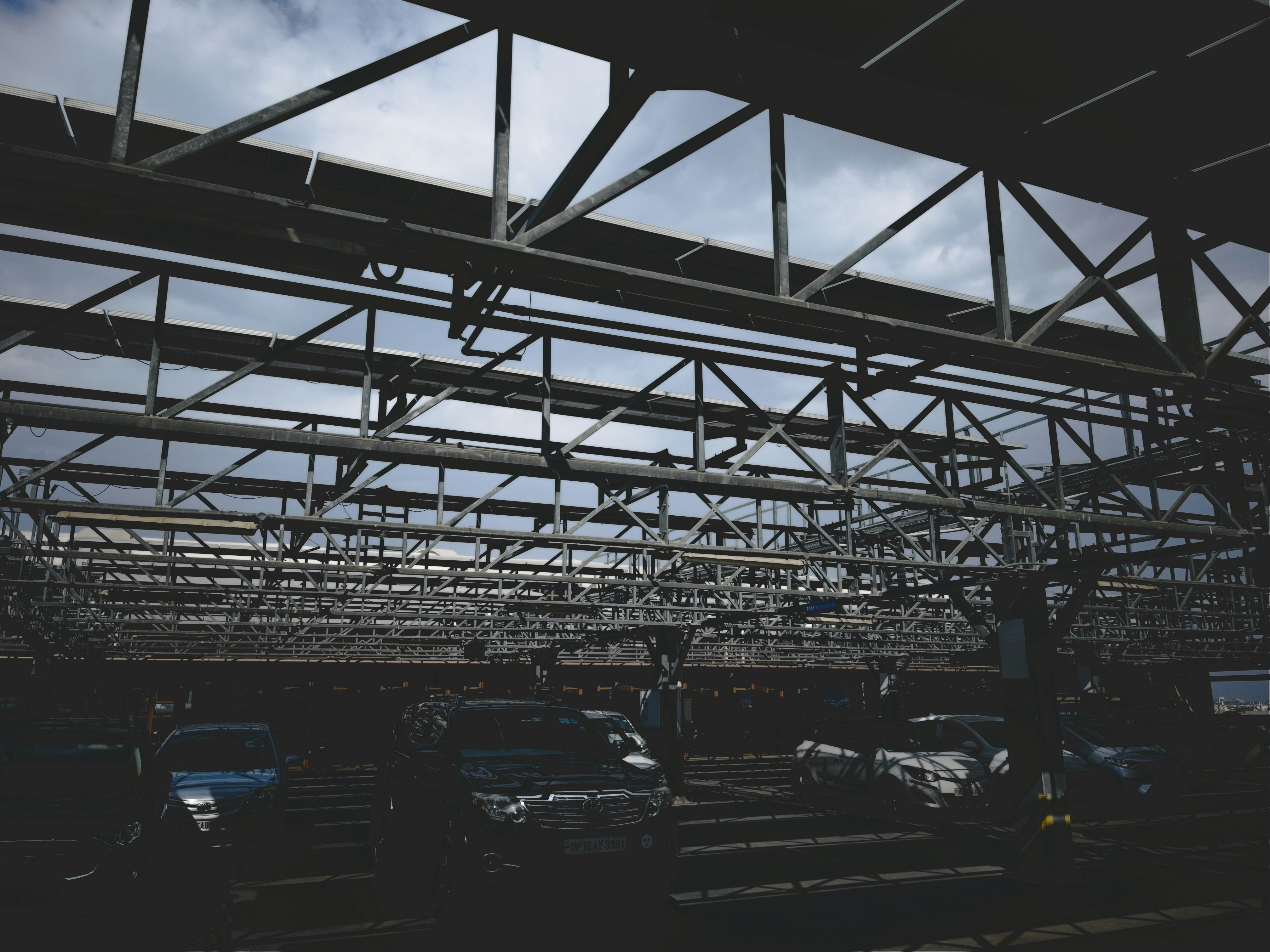 Crisscrossed Steel Canopy Looms Above a Dim Parking Yard