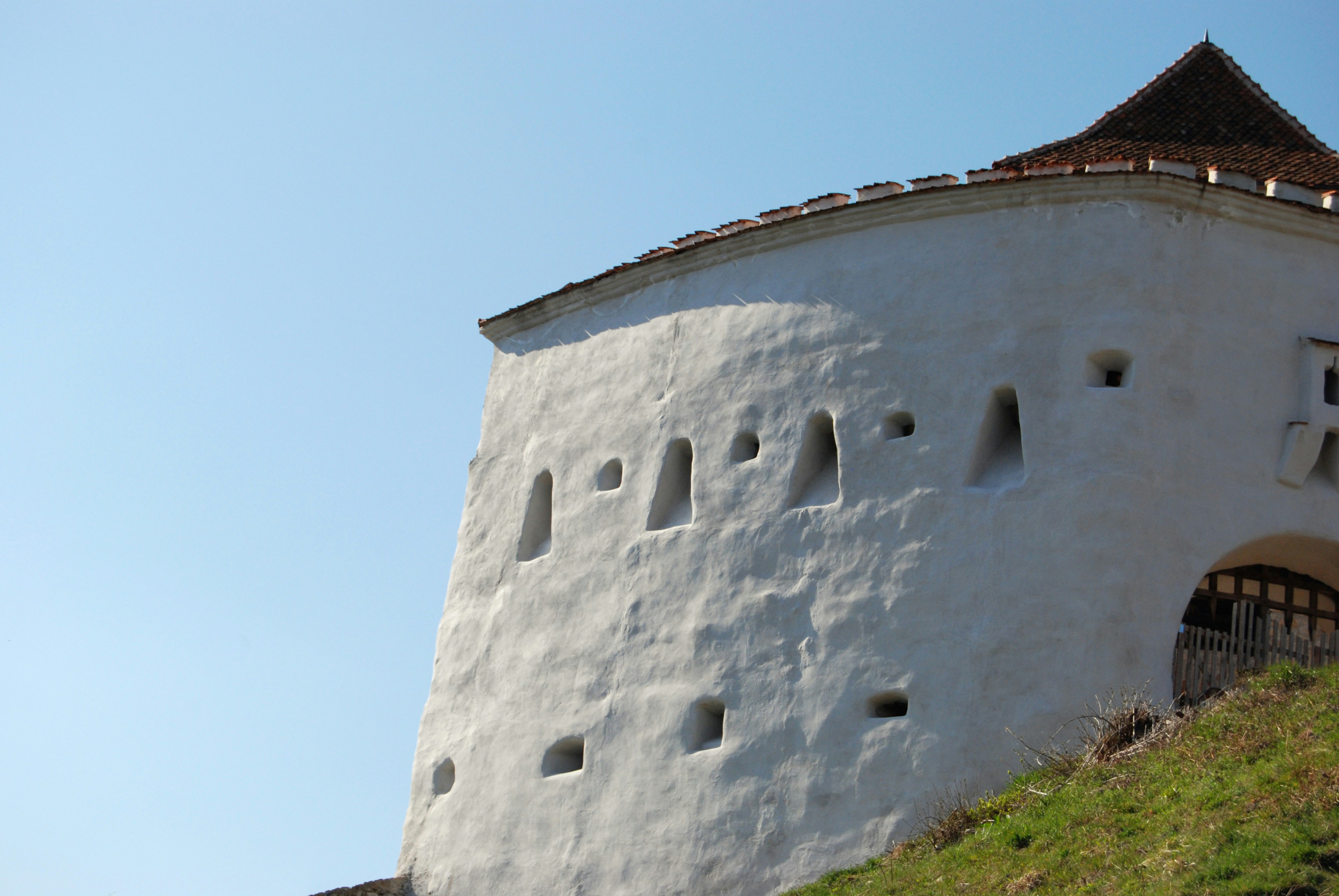 View of the interior wall of Cumidava, the dacian citadel in Râșnov, Romania | a white building with a brown roof on a hill