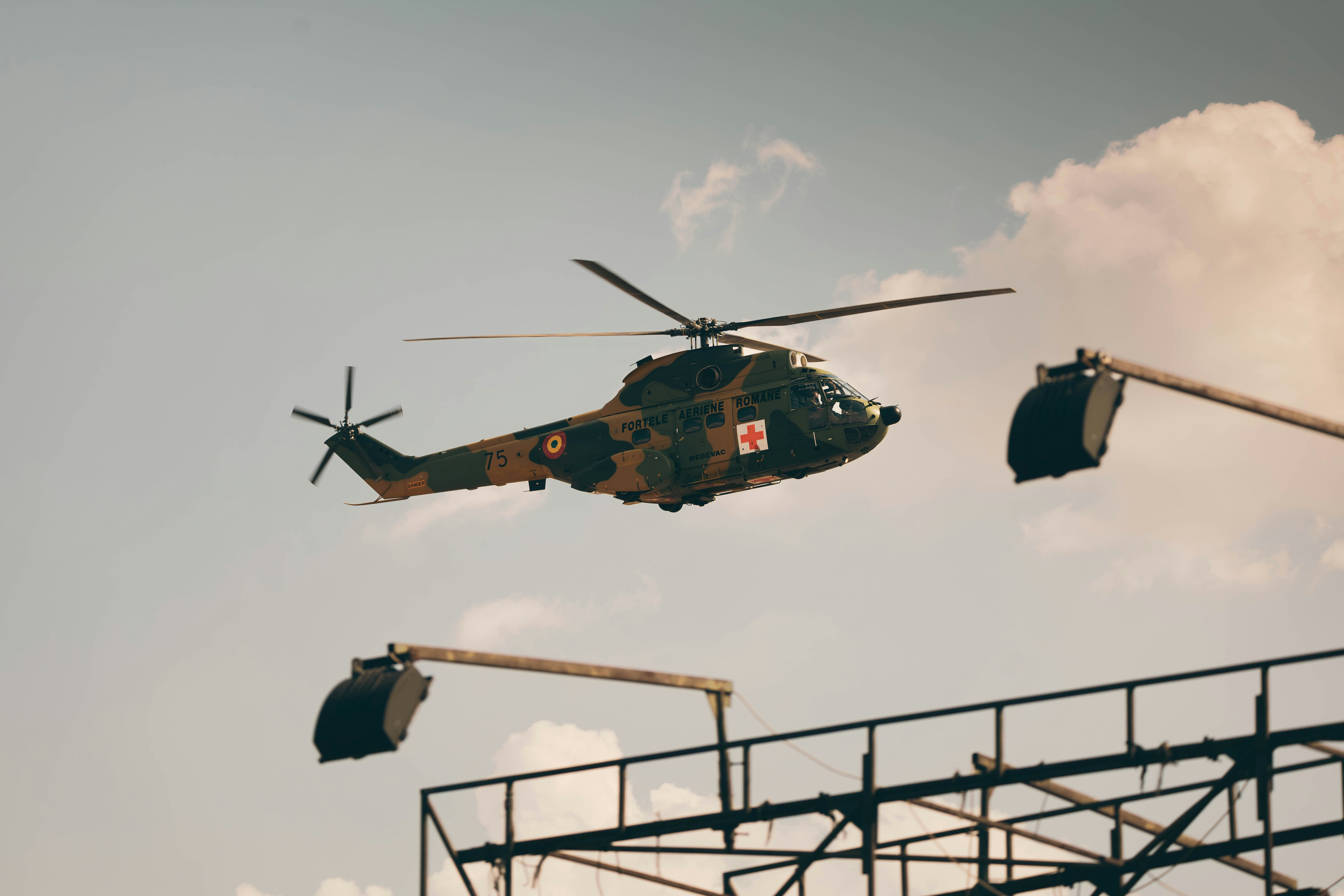Military Helicopter in Mid-Flight Above an Industrial Framework