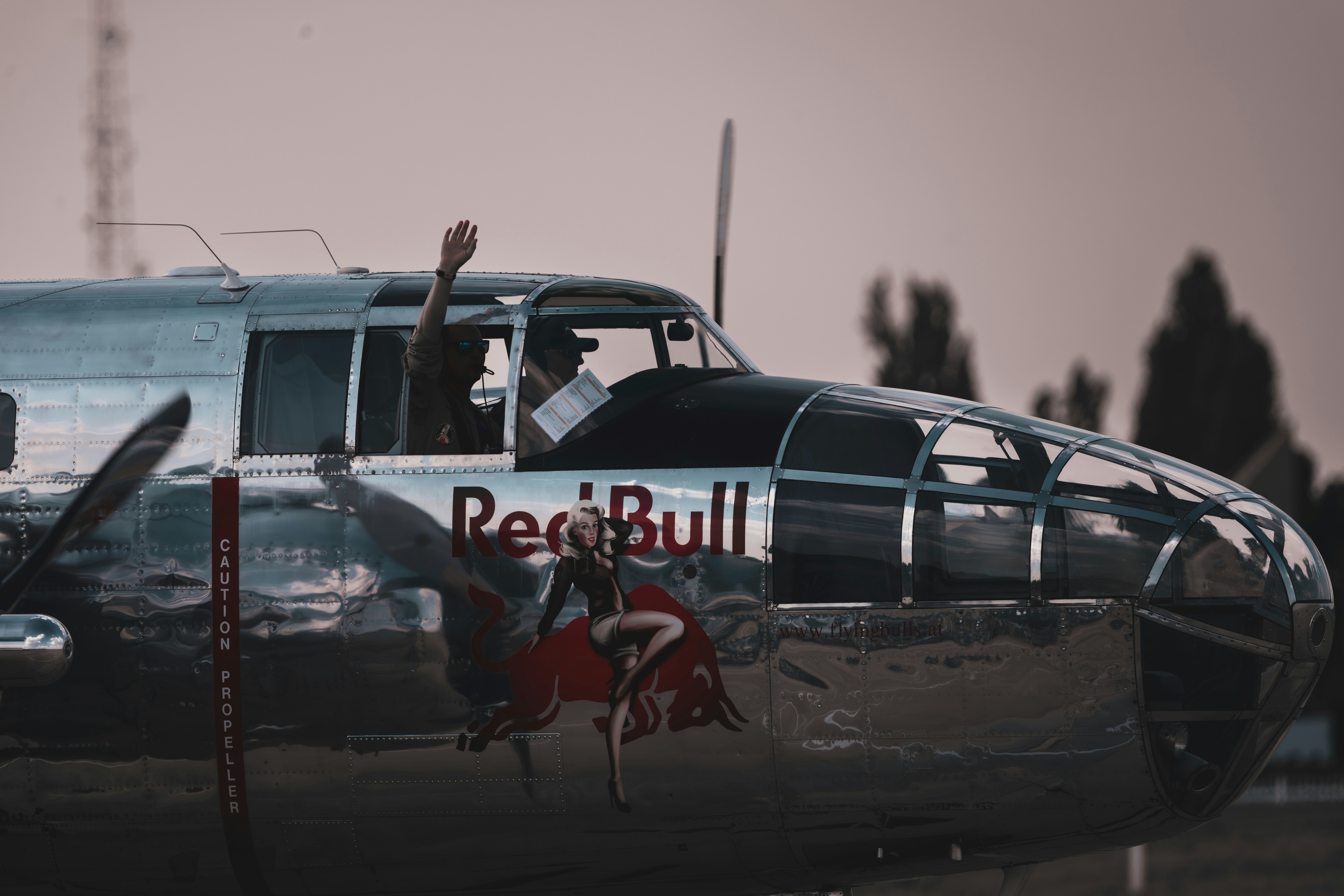 Chrome Relic on the Runway: A Red Bull aircraft gleams as a pilot waves from the cockpit