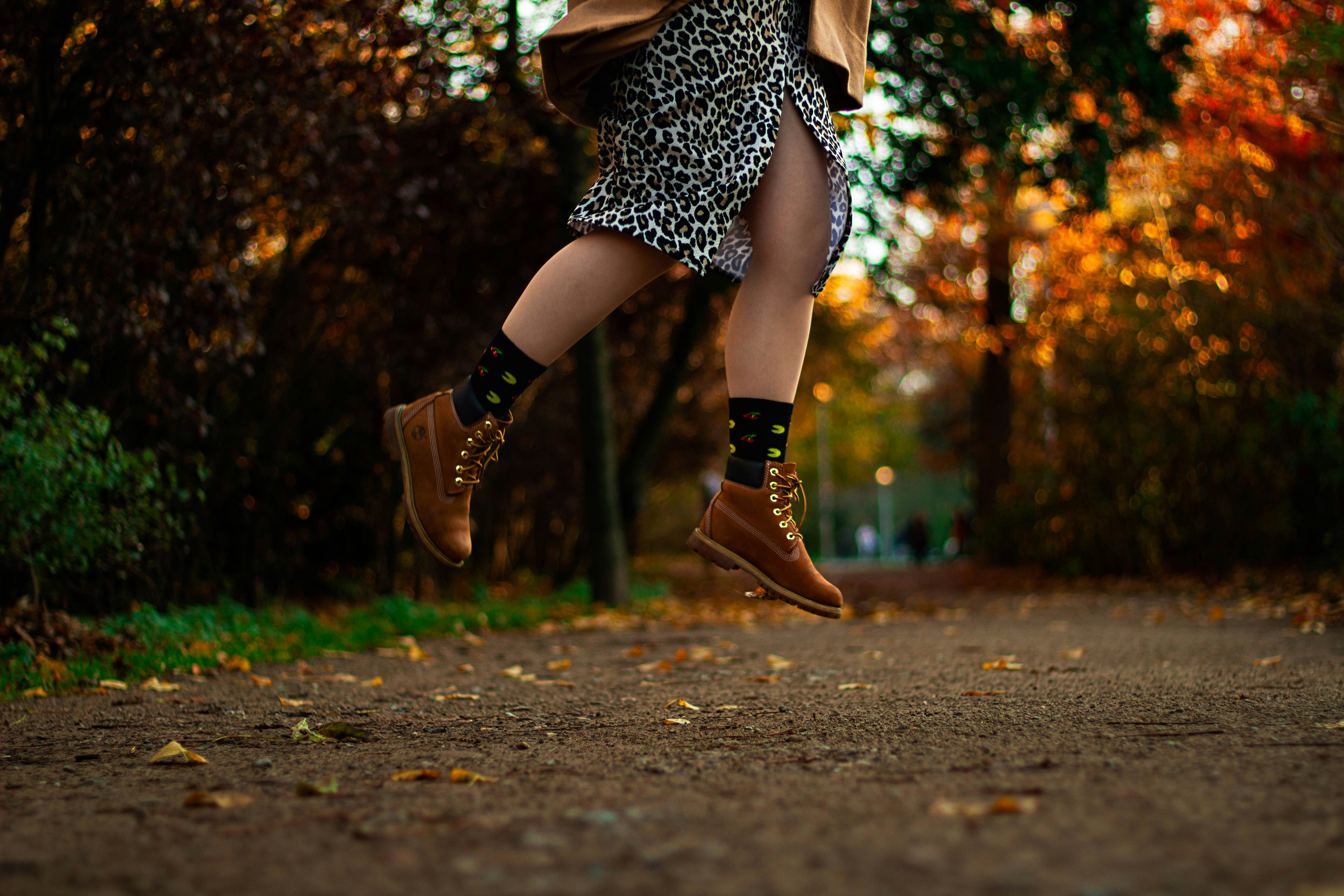 Jumping Through Autumn: Feet in Motion Along a Leaf-Strewn Path