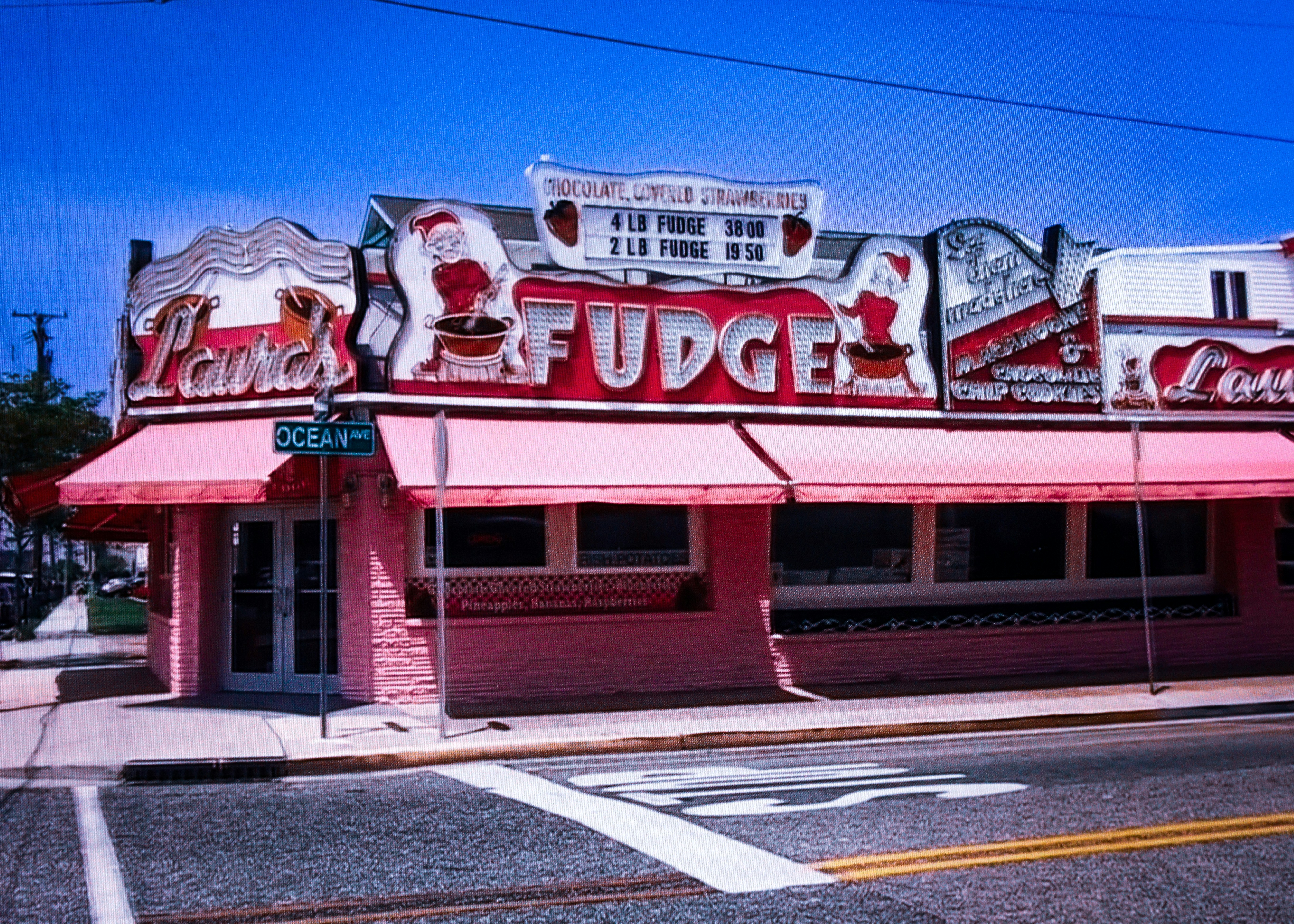 Vintage storefront of Laura's Fudge featuring colorful signage and a pink facade, inviting passersby to indulge in sweet treats.