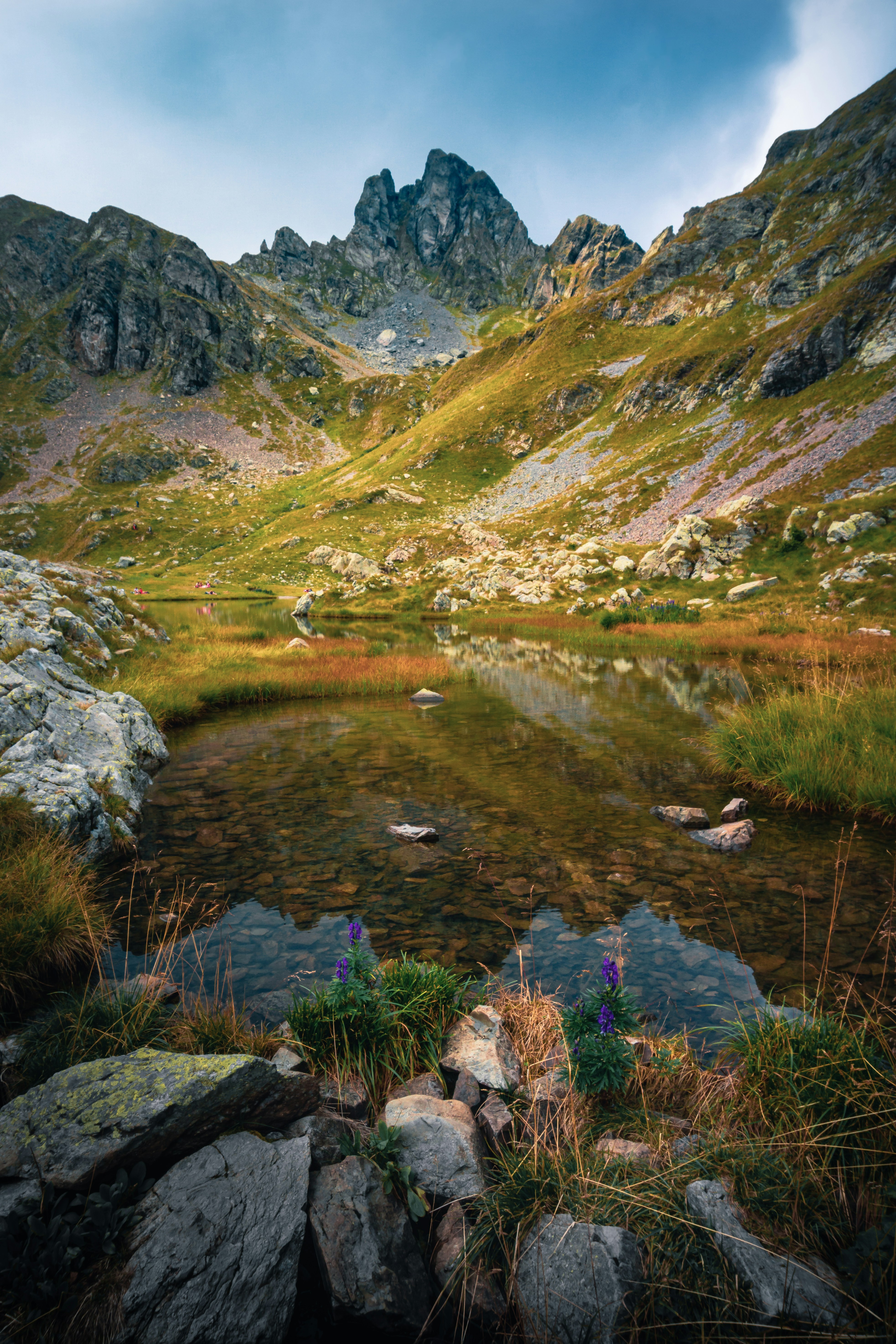 A mountain lake surrounded by grass and rocks photo – Free Wallpaper 4k ...