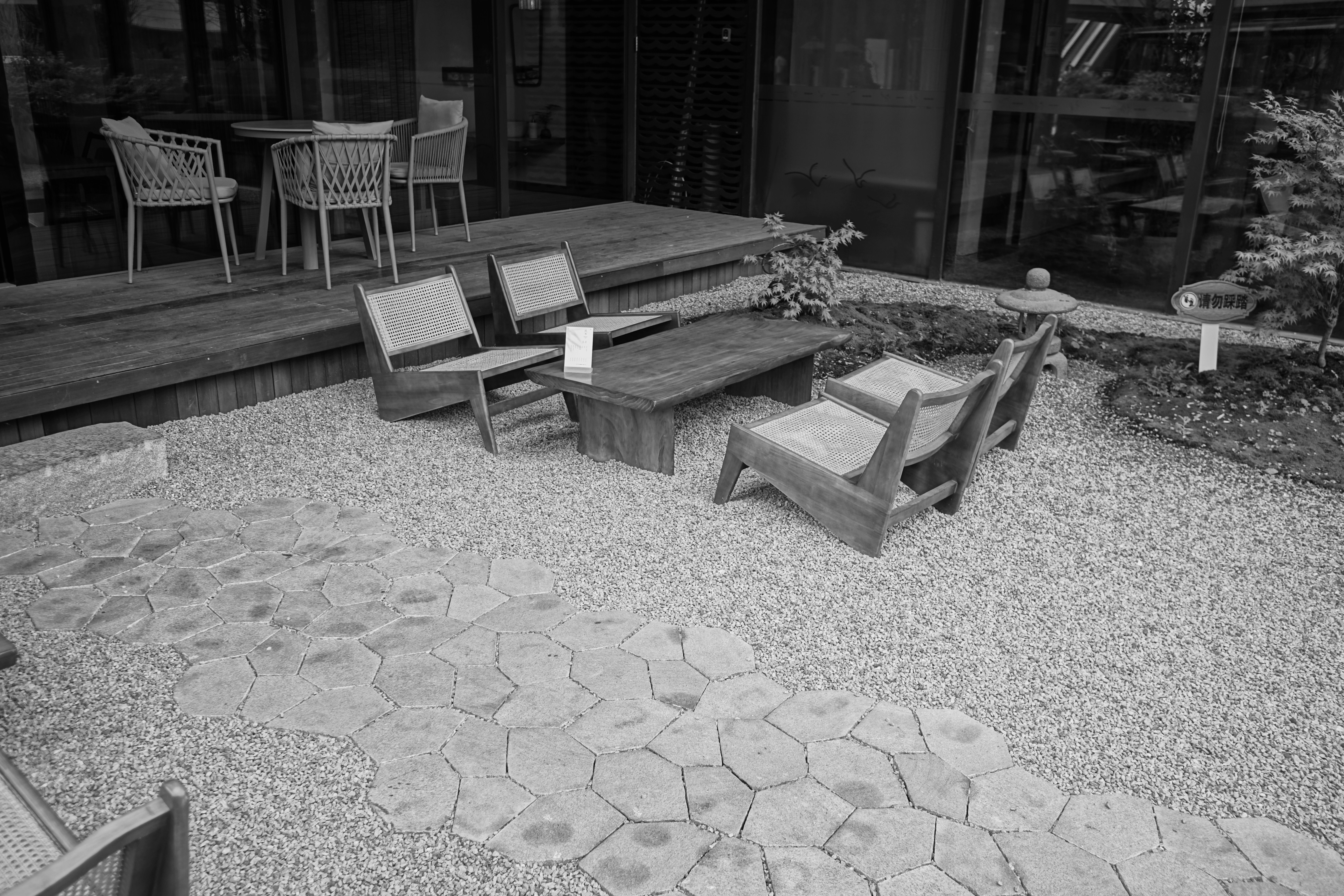 Grayscale Oasis: Central Coffee Table Framed by Wooden Lounge Chairs on a Pebble Patio