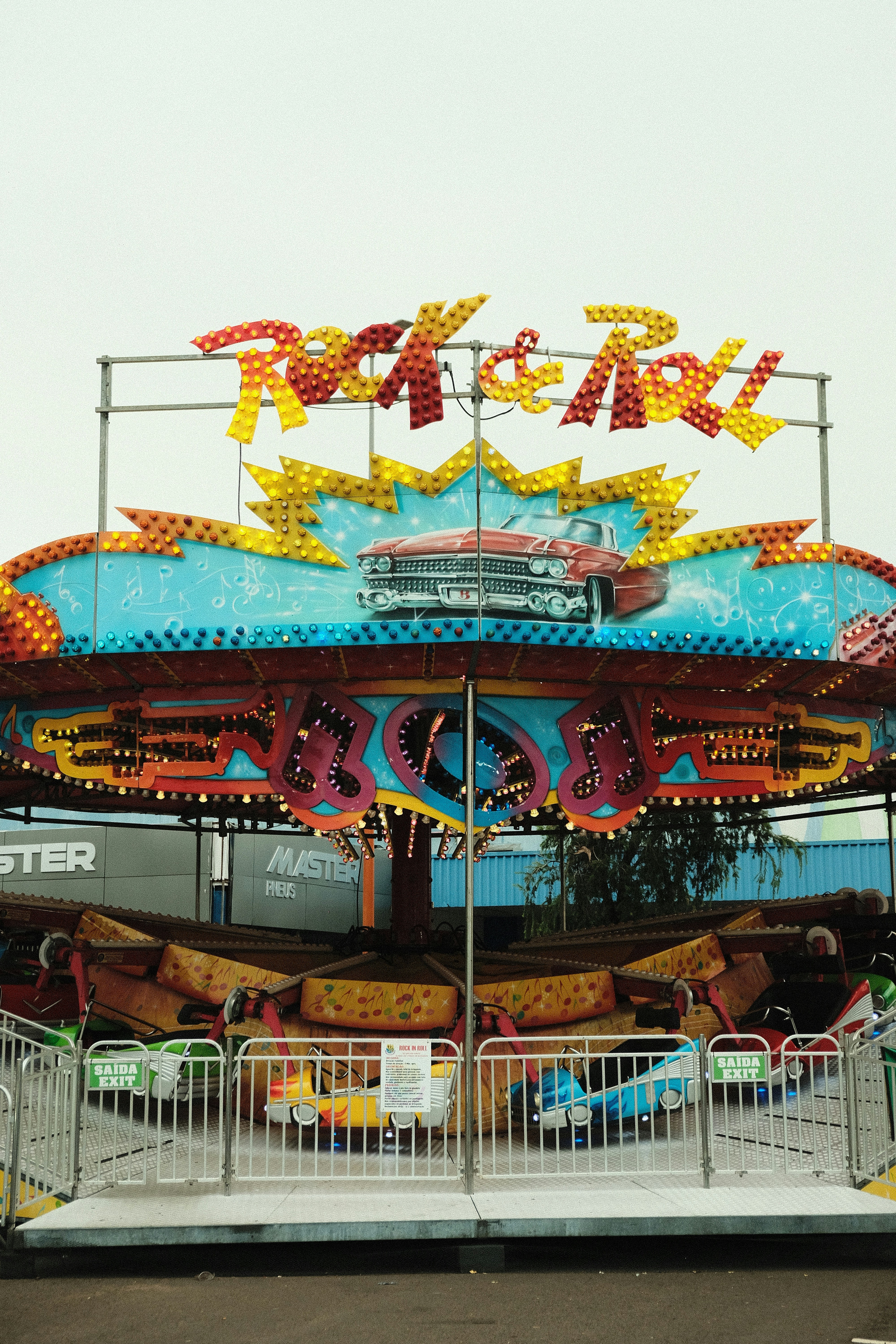 Neon Rock ’n’ Roll Sign Over a Vintage Car Carousel: A Colorful Carnival Facade