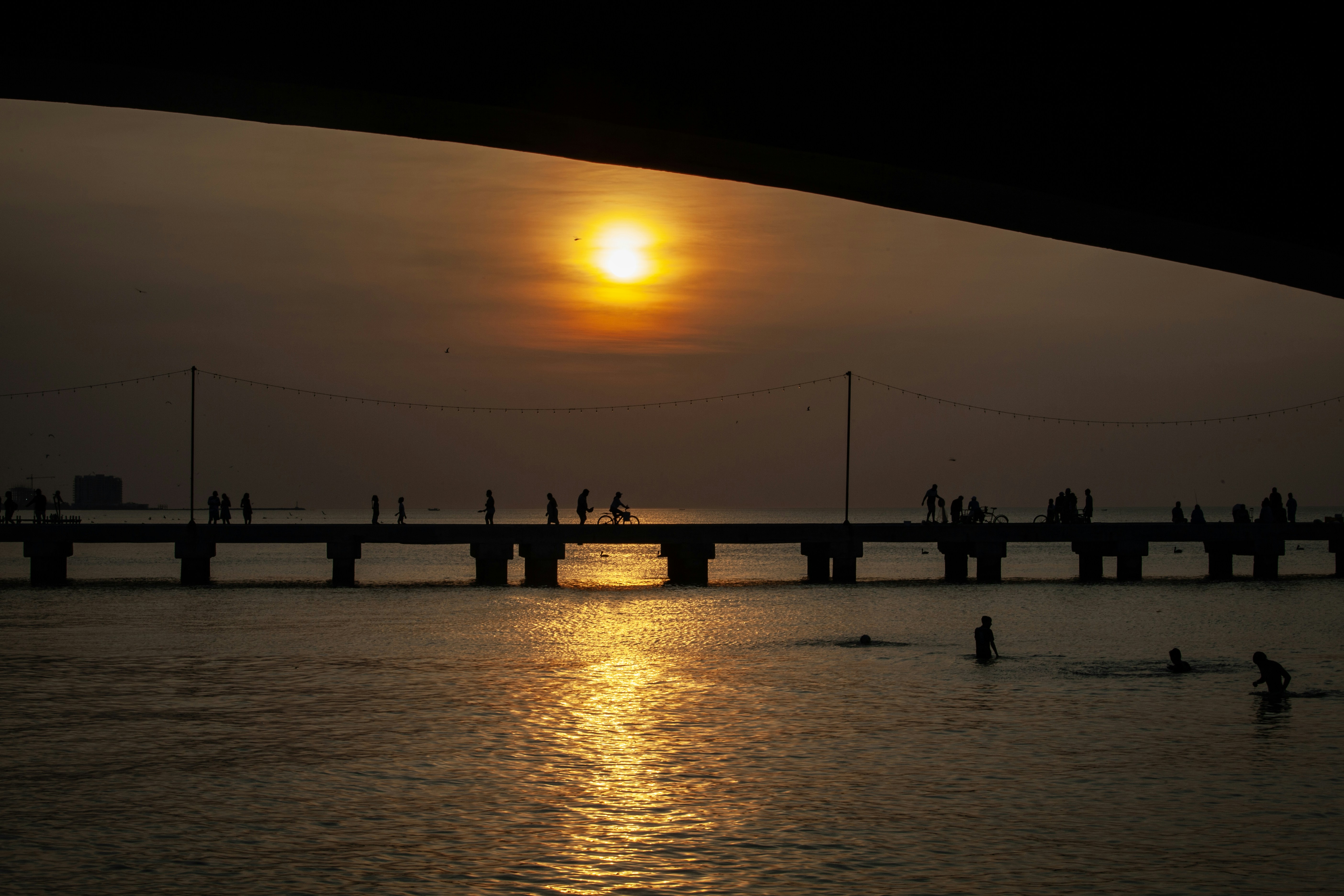 Sunset Pier: Golden Ripples and Silent Silhouettes Beneath the Bridge