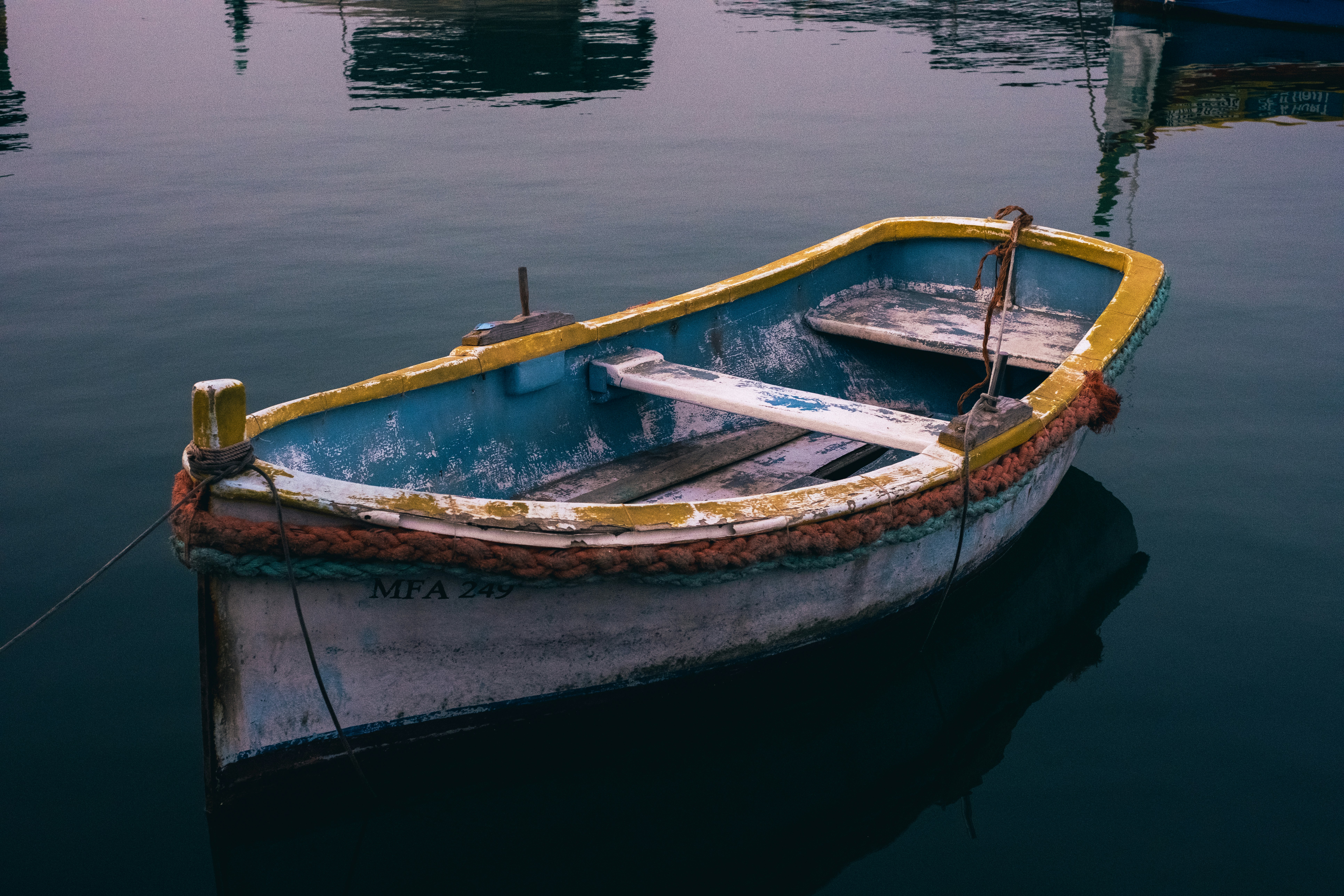 A blue and yellow boat floating on top of a body of water photo – Free ...