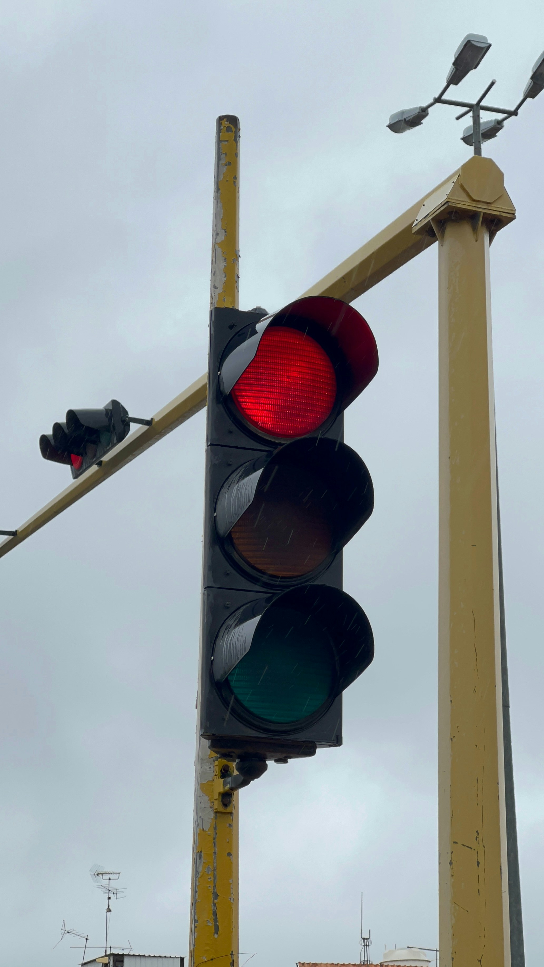 Crimson Stoplight Framed by Weathered Poles Under Grey Skies