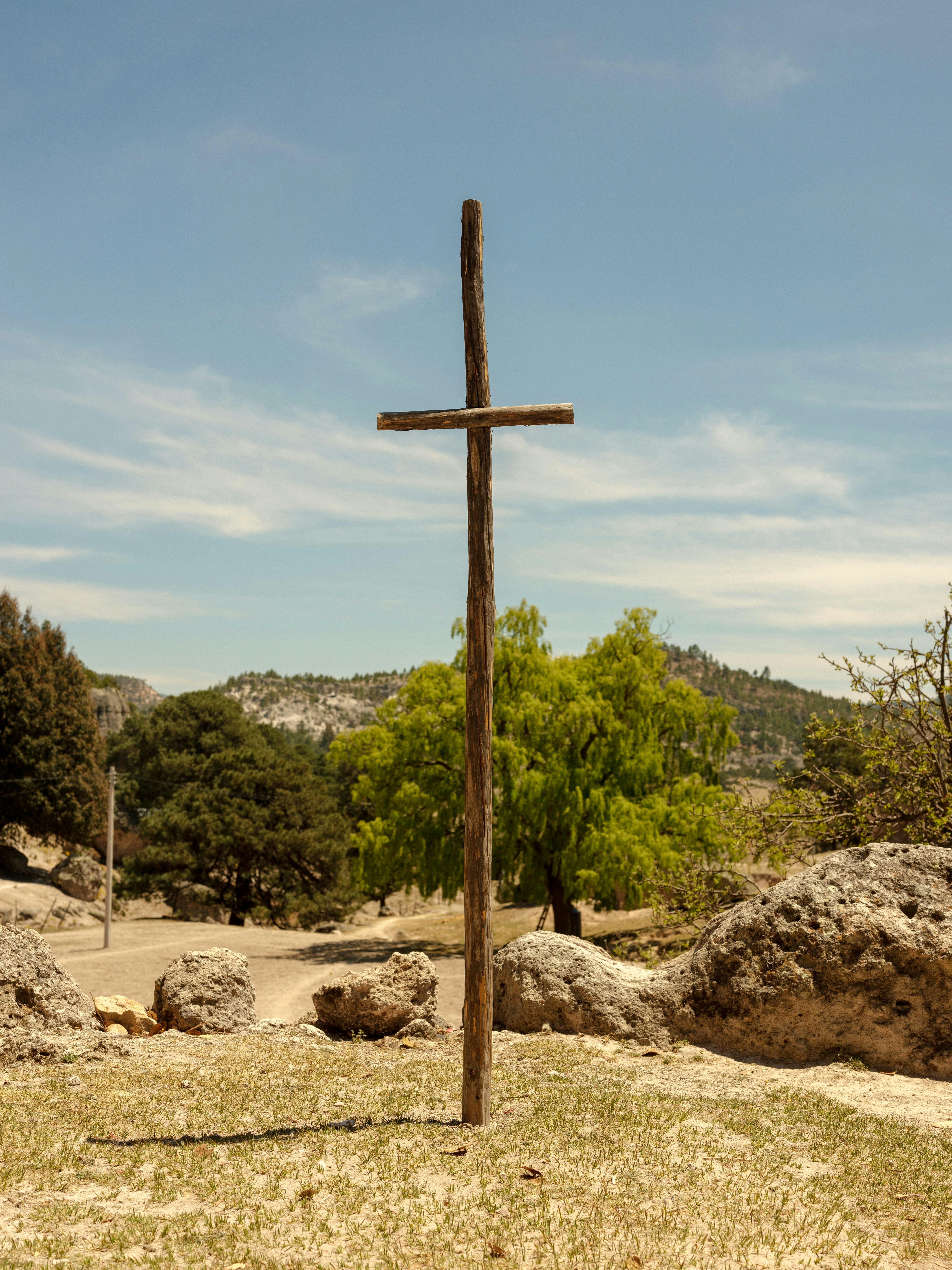 A wooden cross sitting in the middle of a field photo – Free Cross ...