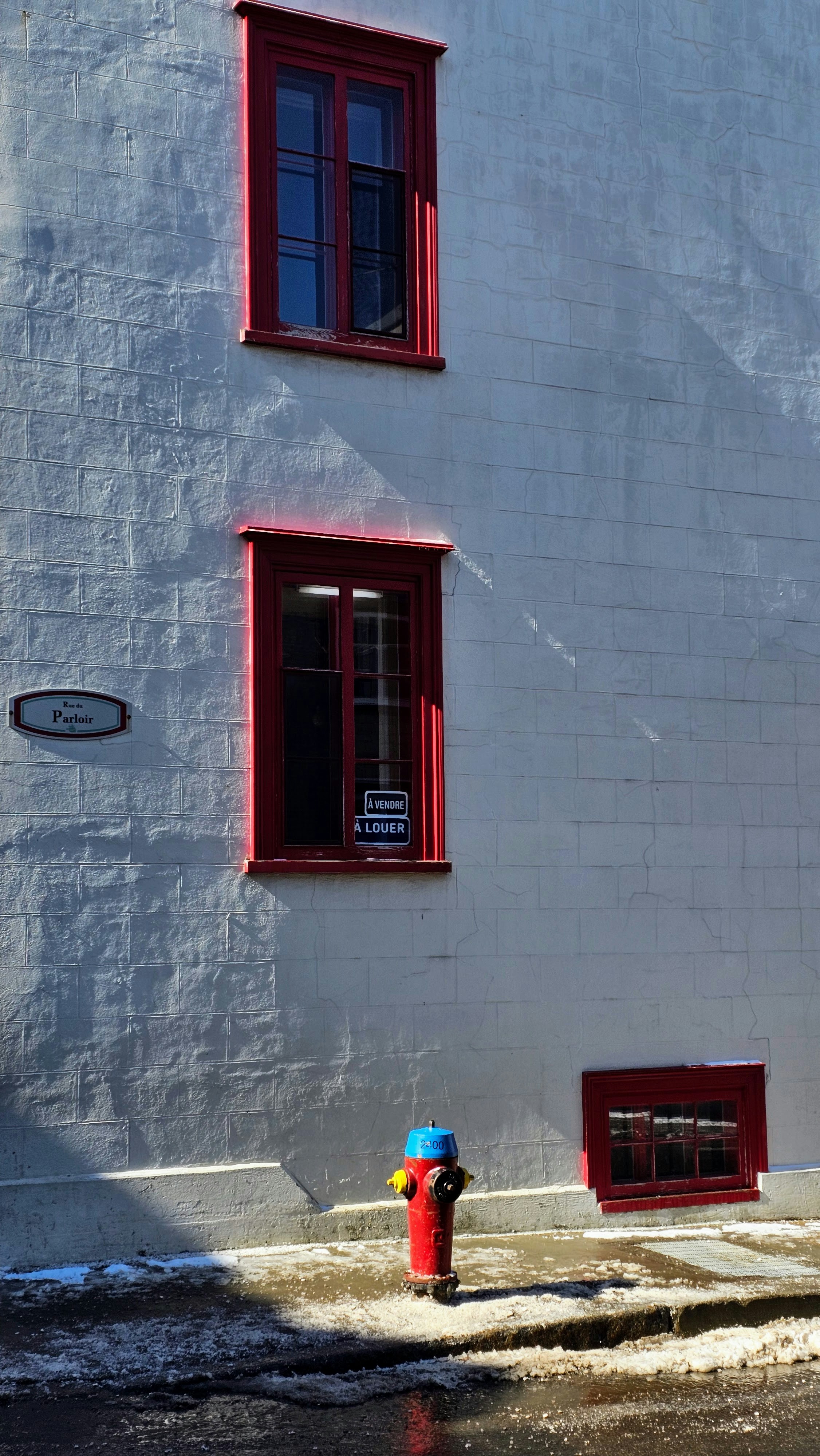 A red and blue fire hydrant in front of a white building photo – Free ...
