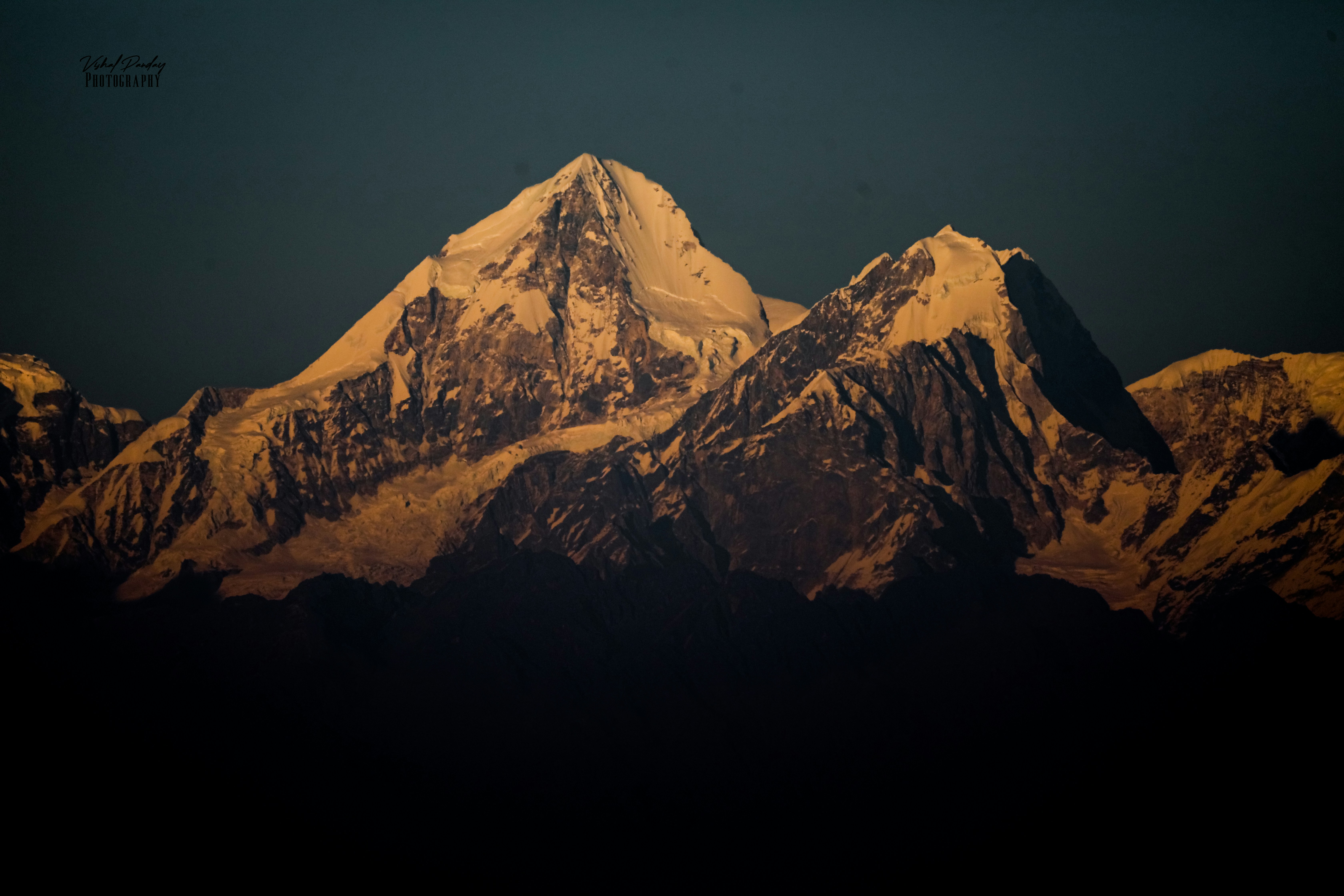 Snow-capped mountains illuminated by the soft glow of twilight, showcasing their rugged beauty and grandeur.