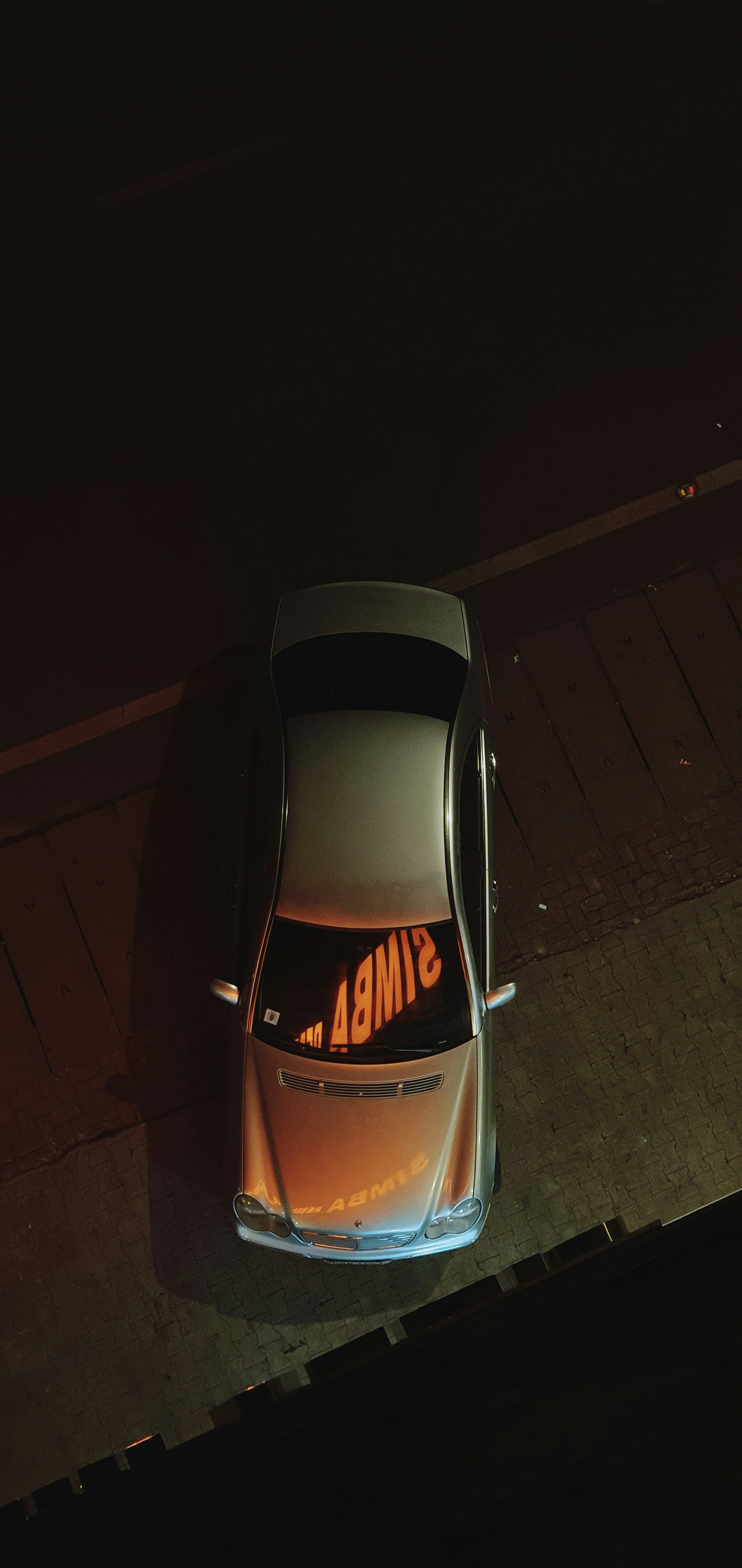 Neon Reflections on a Silver Coupe: A Night-Top View