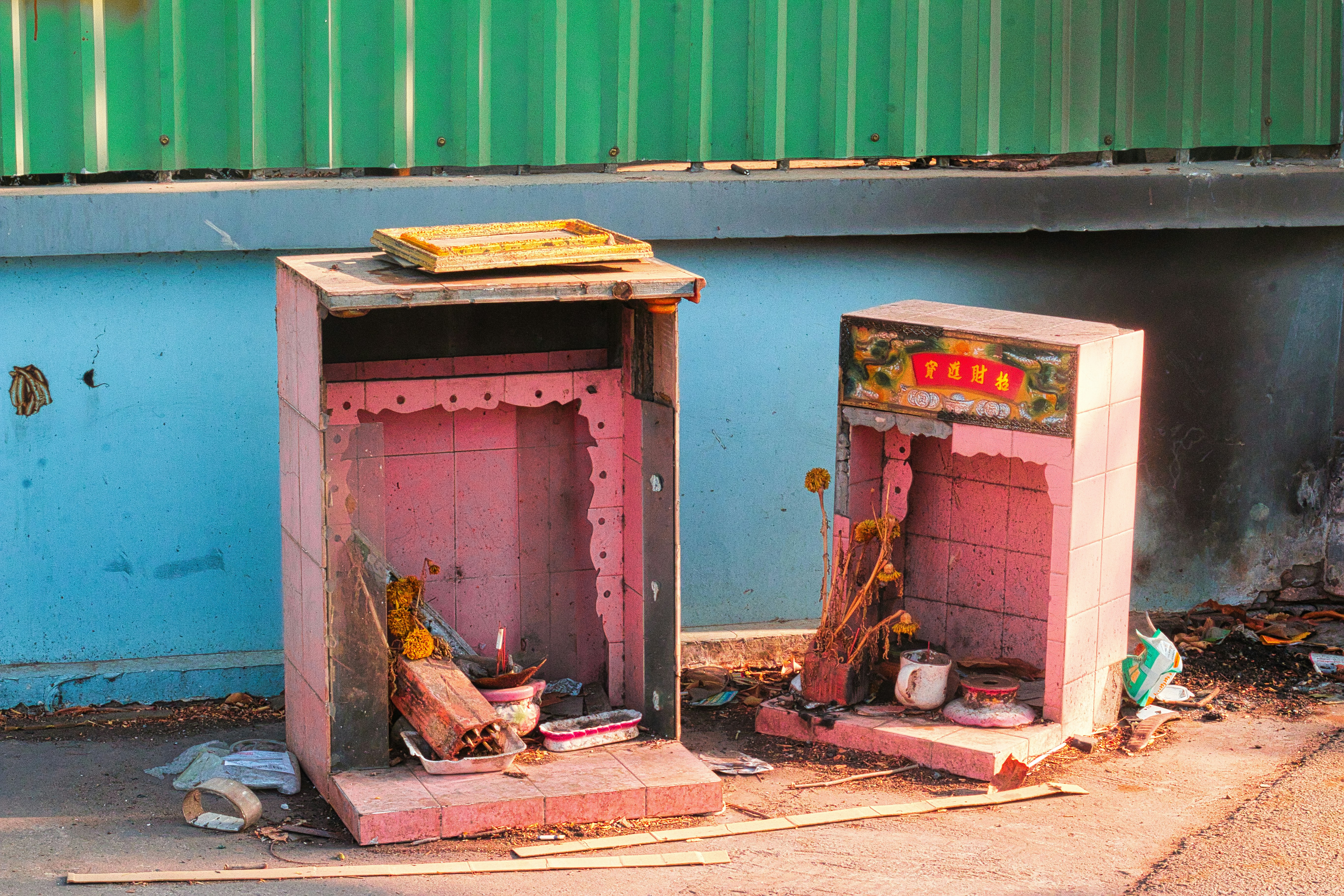 Two Pink Shrines by a Blue Wall: Quiet Ritual Amid Debris