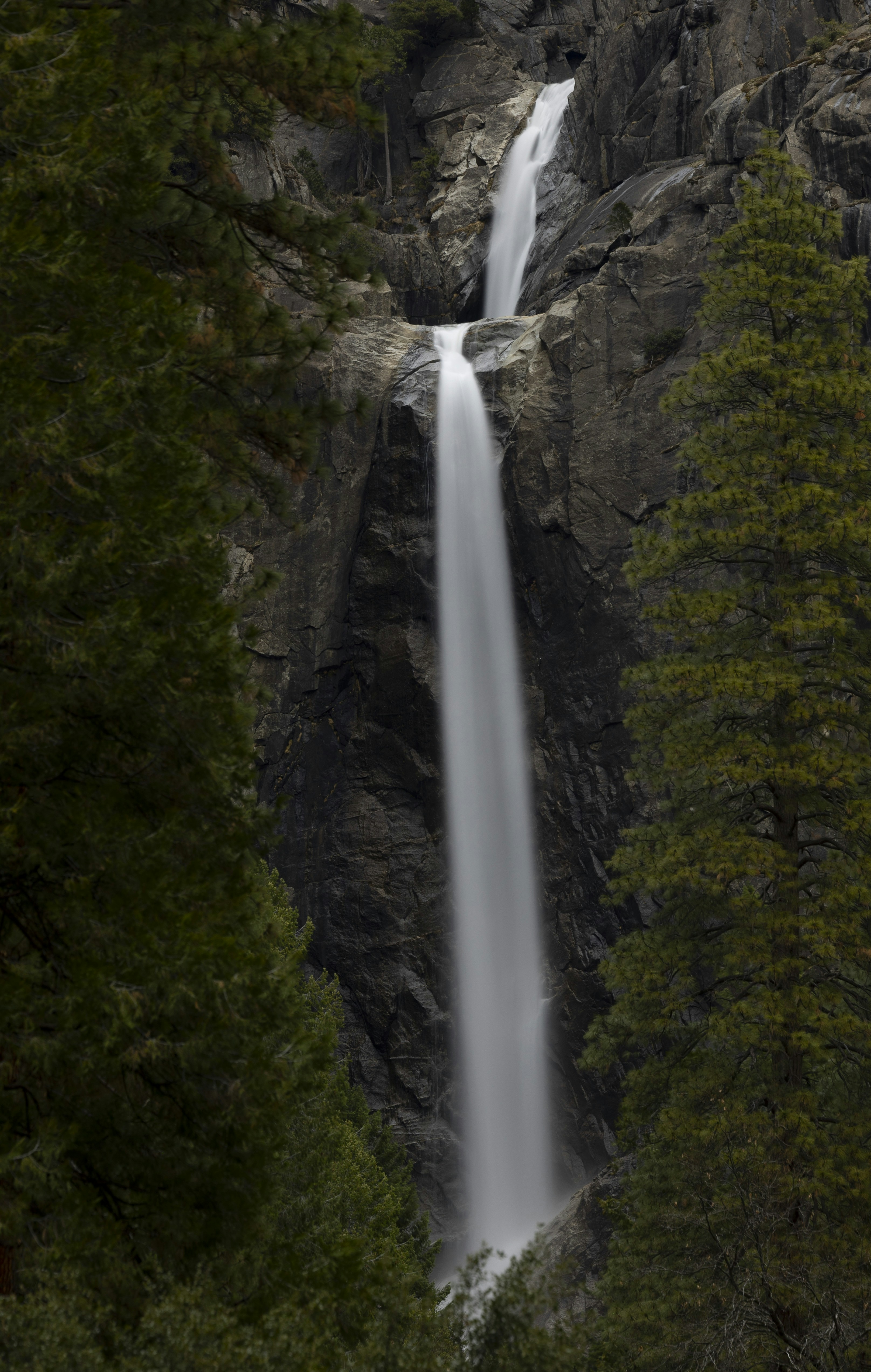 A tall waterfall is seen through the trees photo – Free Nature Image on ...