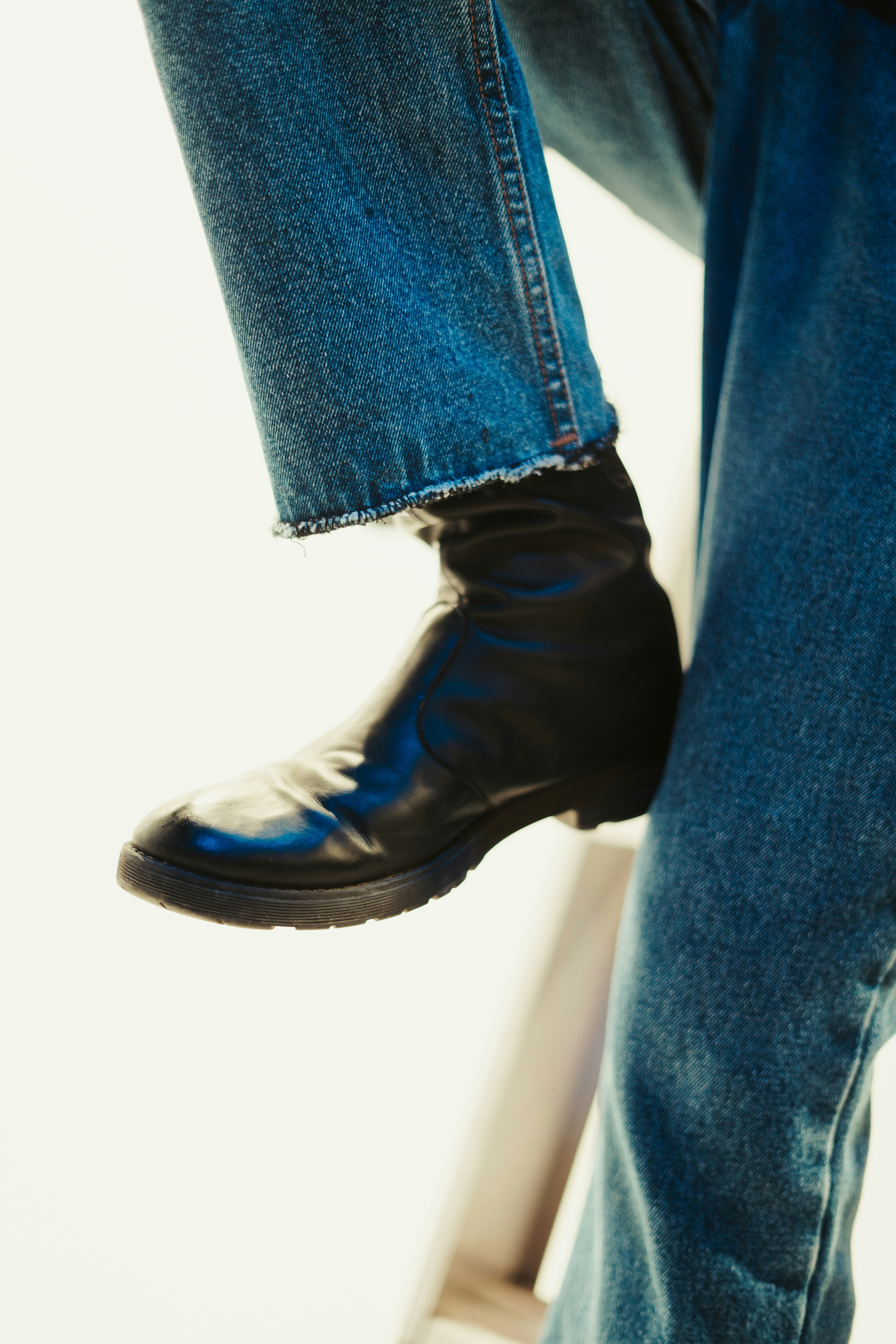 A man in jeans and black boots sitting on a stool photo – Free Denim ...