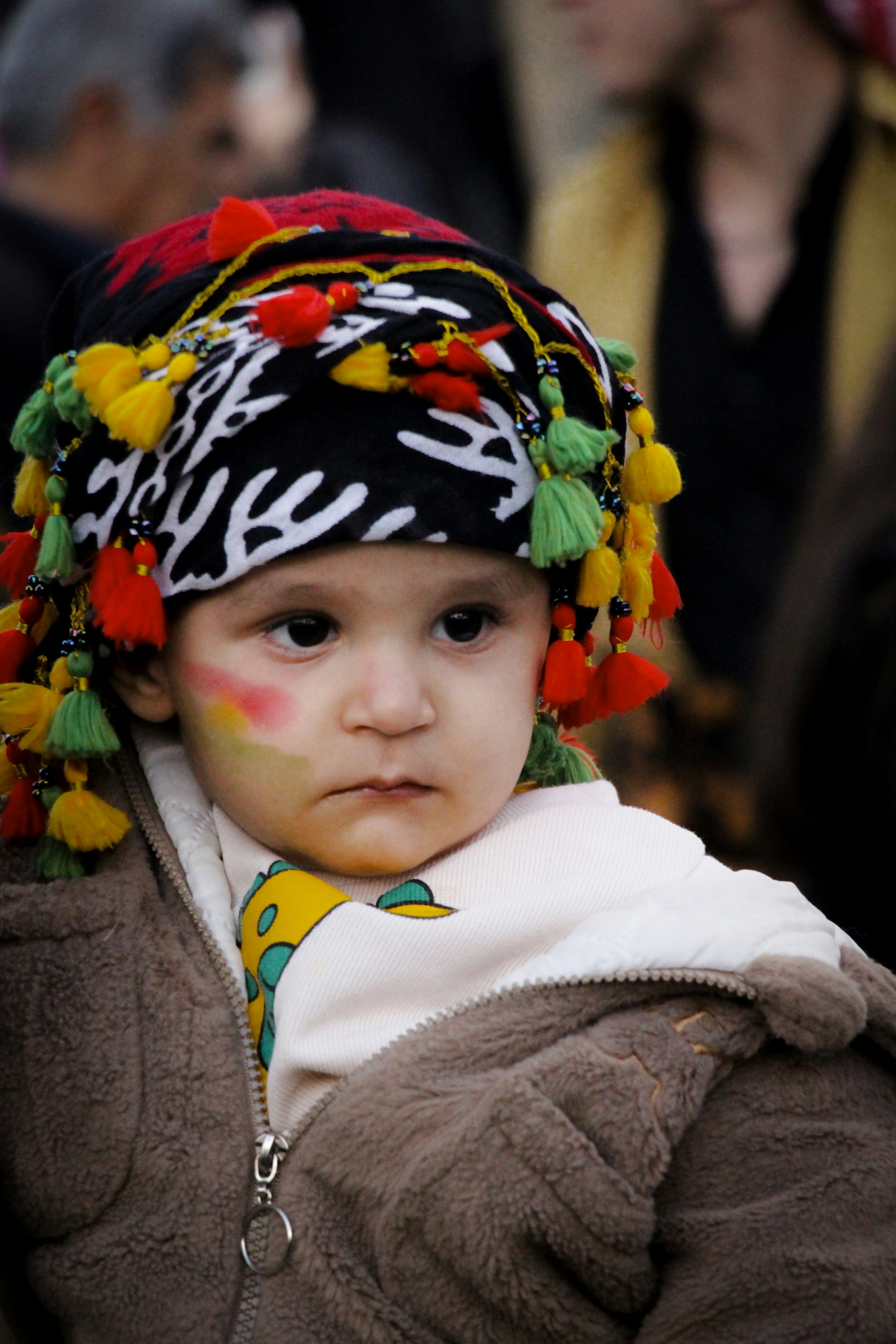Tassel Crown and Painted Gaze: A Baby Amid Festive Colors