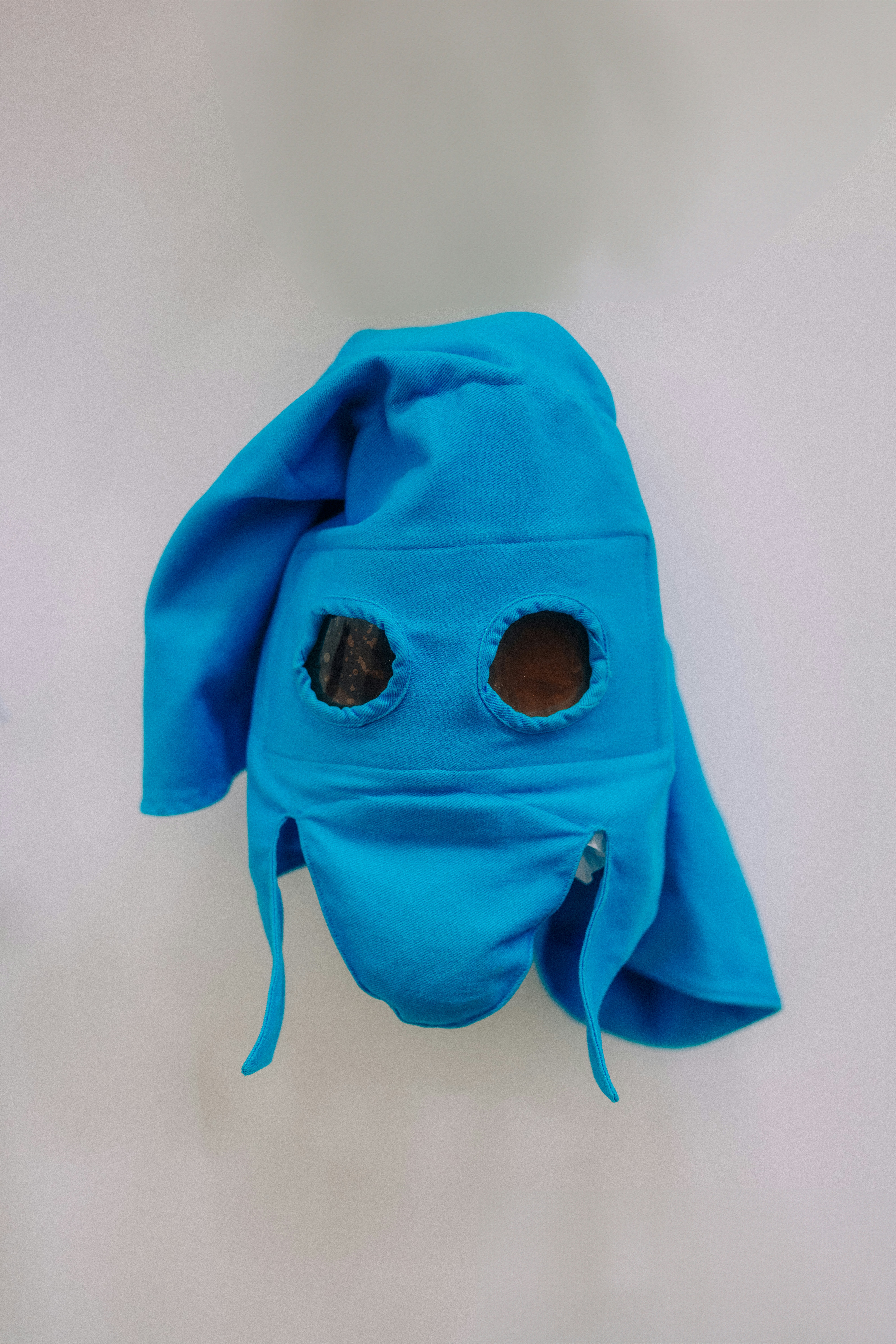 Azure Fabric Creature: A Blue Plush Head with Eye Holes Against a Minimal Backdrop
