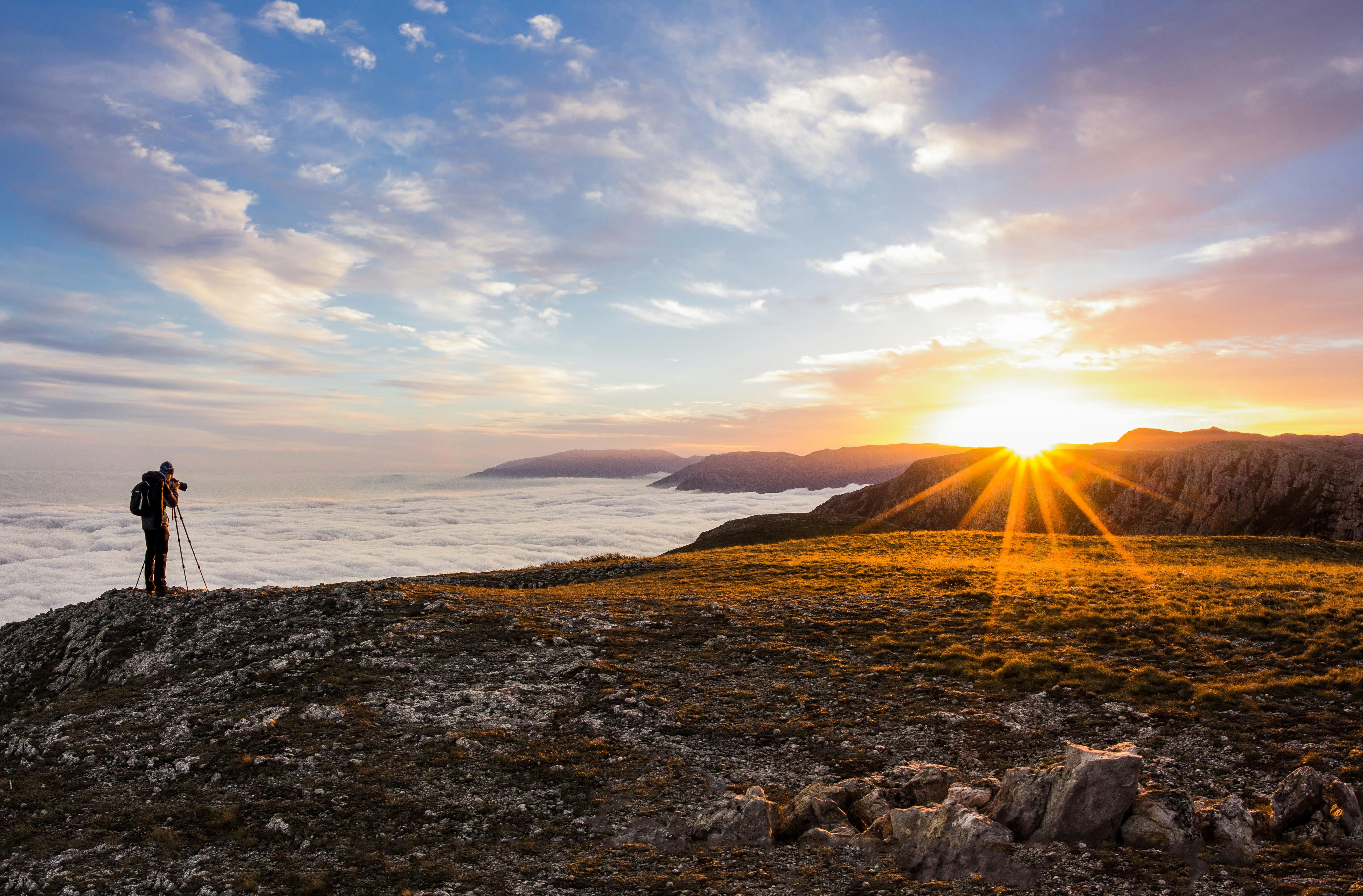 Ein Mann, der mit einem Rucksack auf dem Gipfel eines Berges steht Foto ...