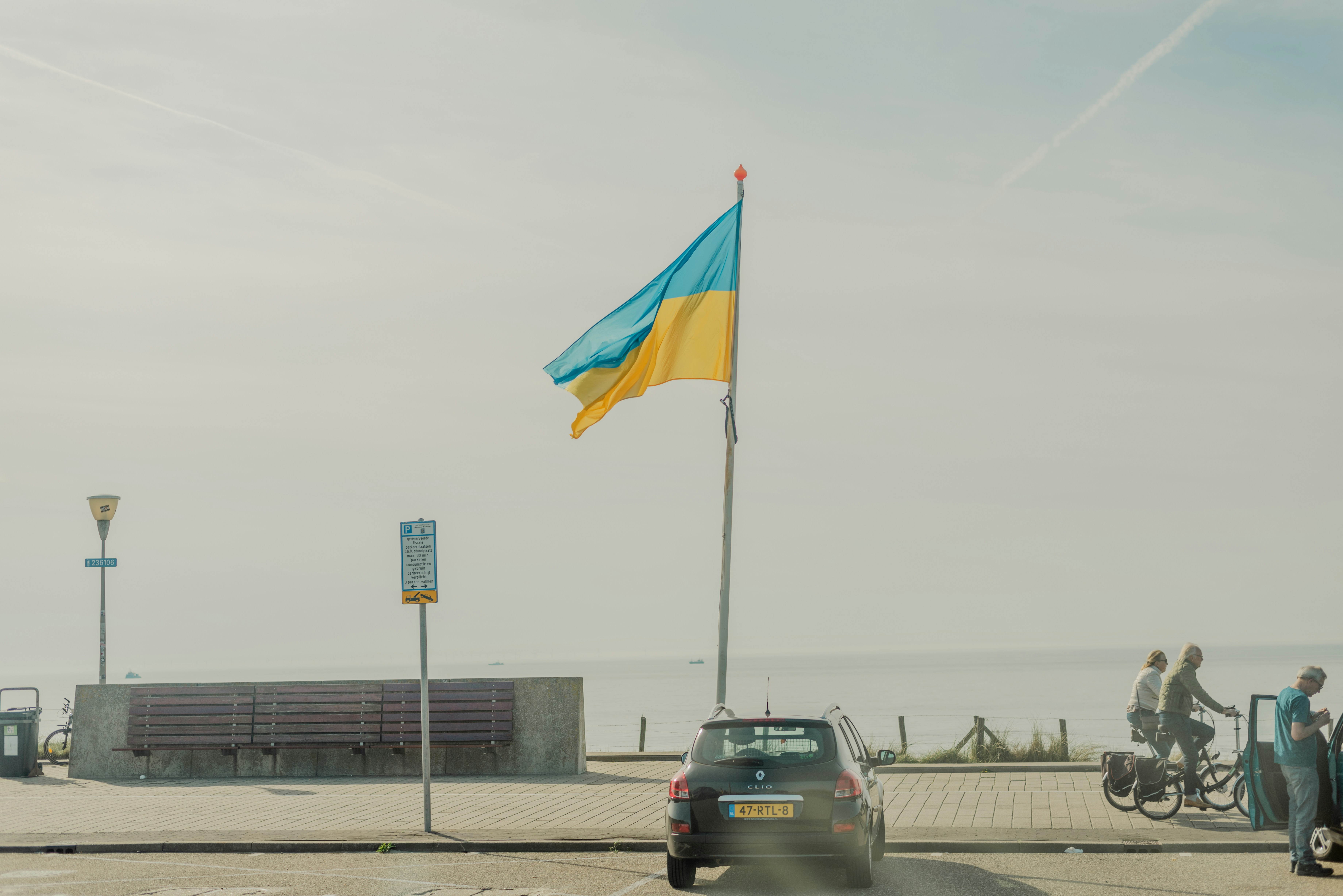 A car driving down a street next to a flag pole photo – Free Car Image ...