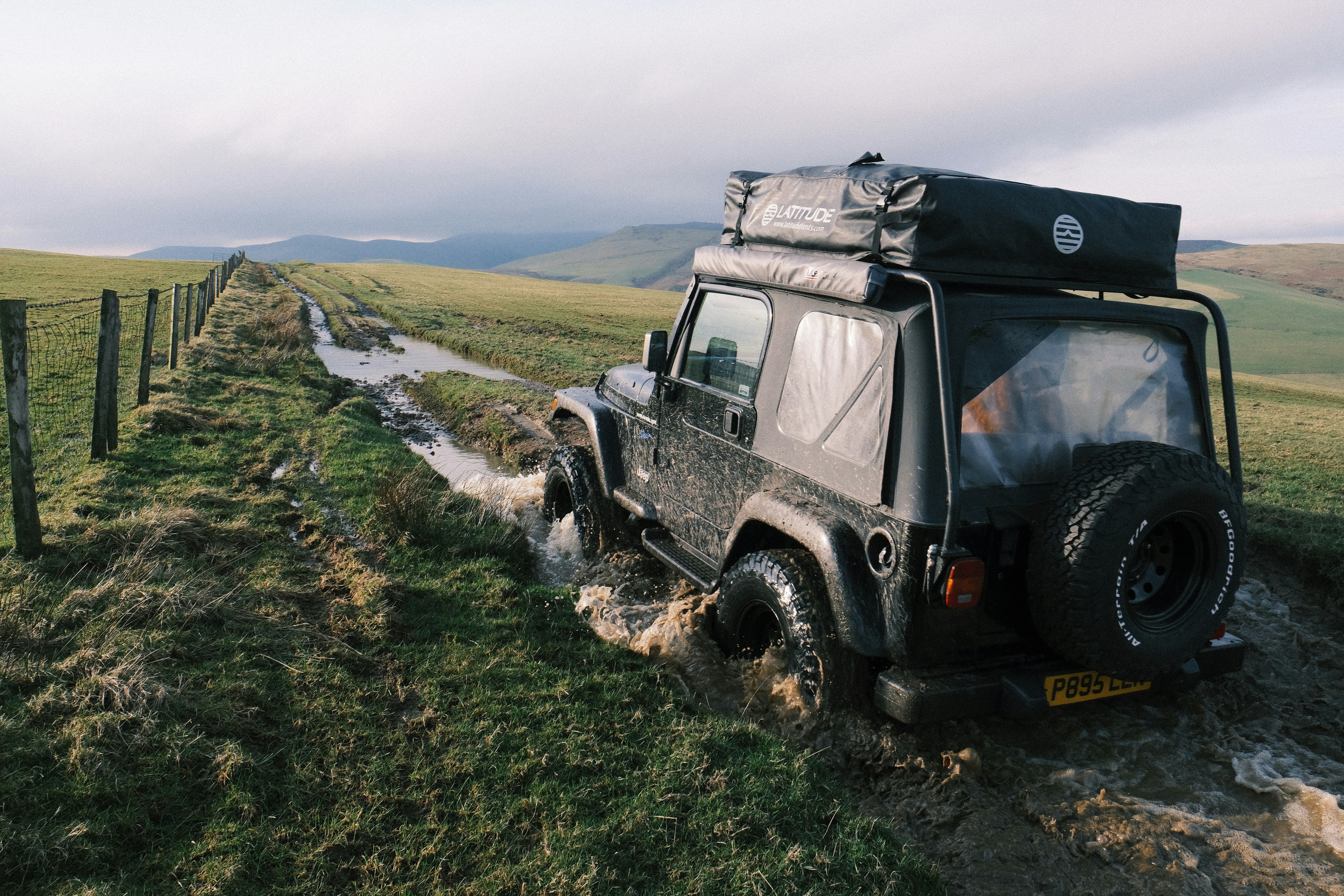 Moorland Scramble: Mud-Splattered Jeep Conquers a Narrow Moor Road