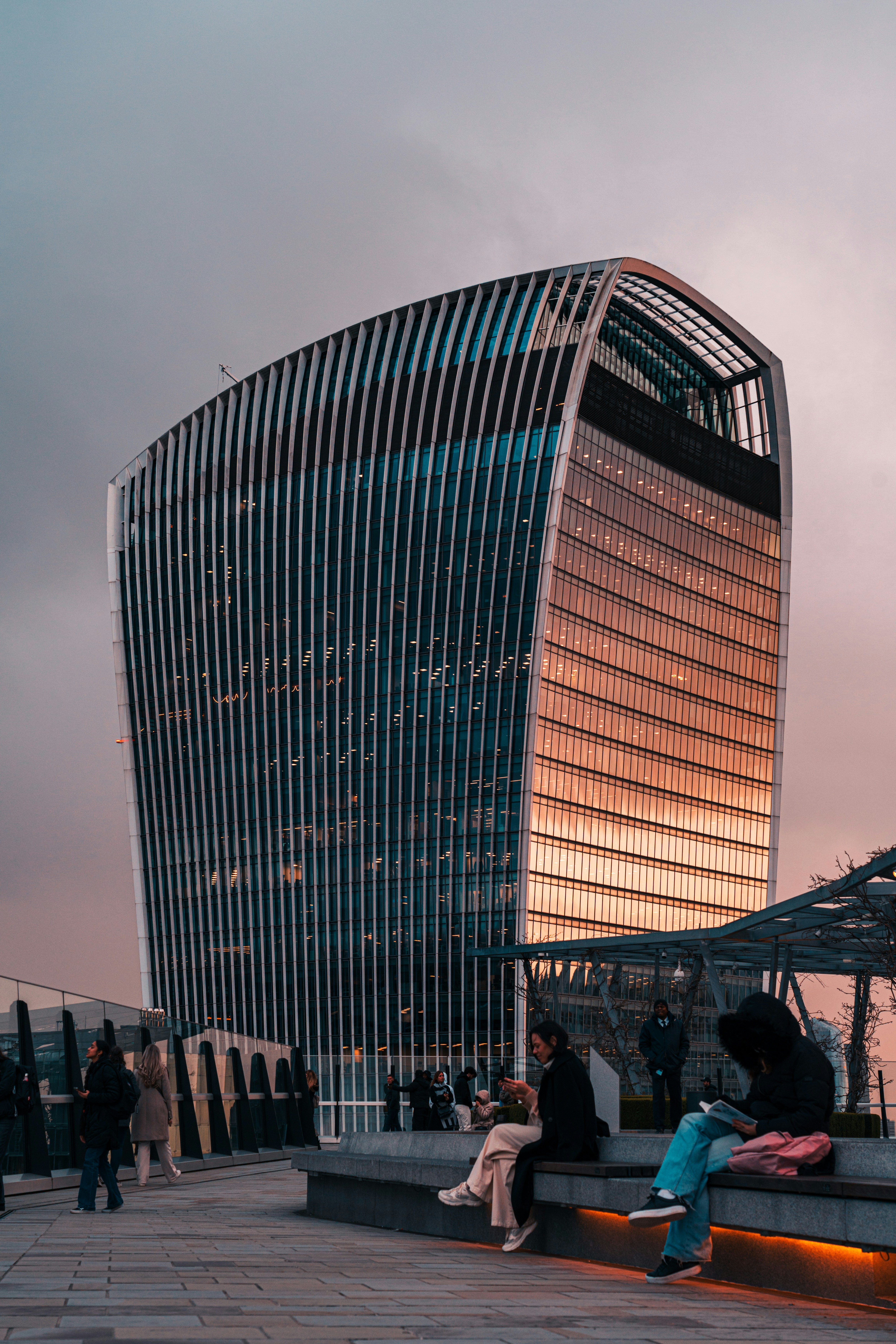 A group of people sitting outside of a tall building photo – Free Full ...