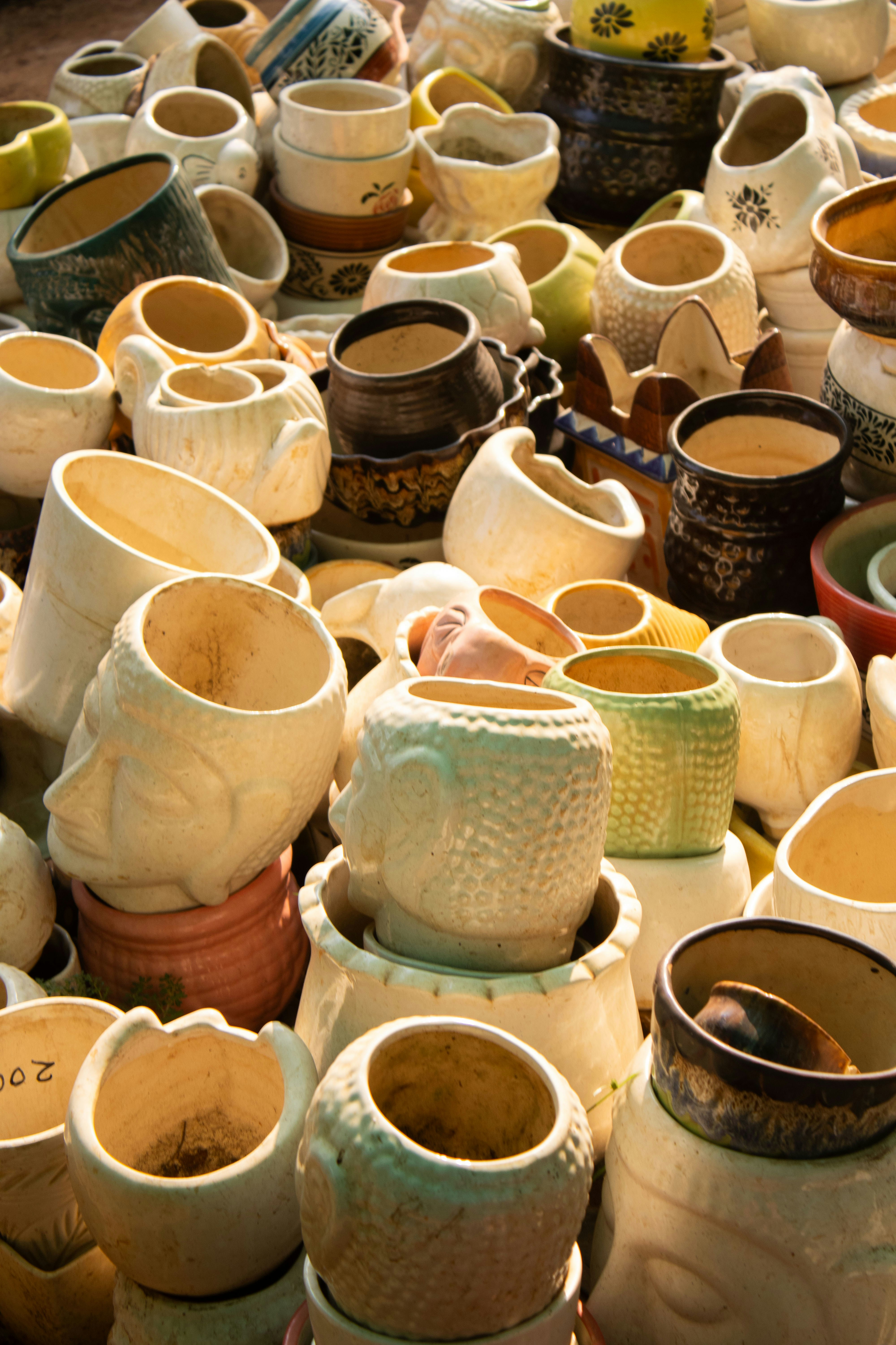 A vibrant array of ceramic pots and planters, showcasing intricate designs and varied colors, displayed in a bustling market.