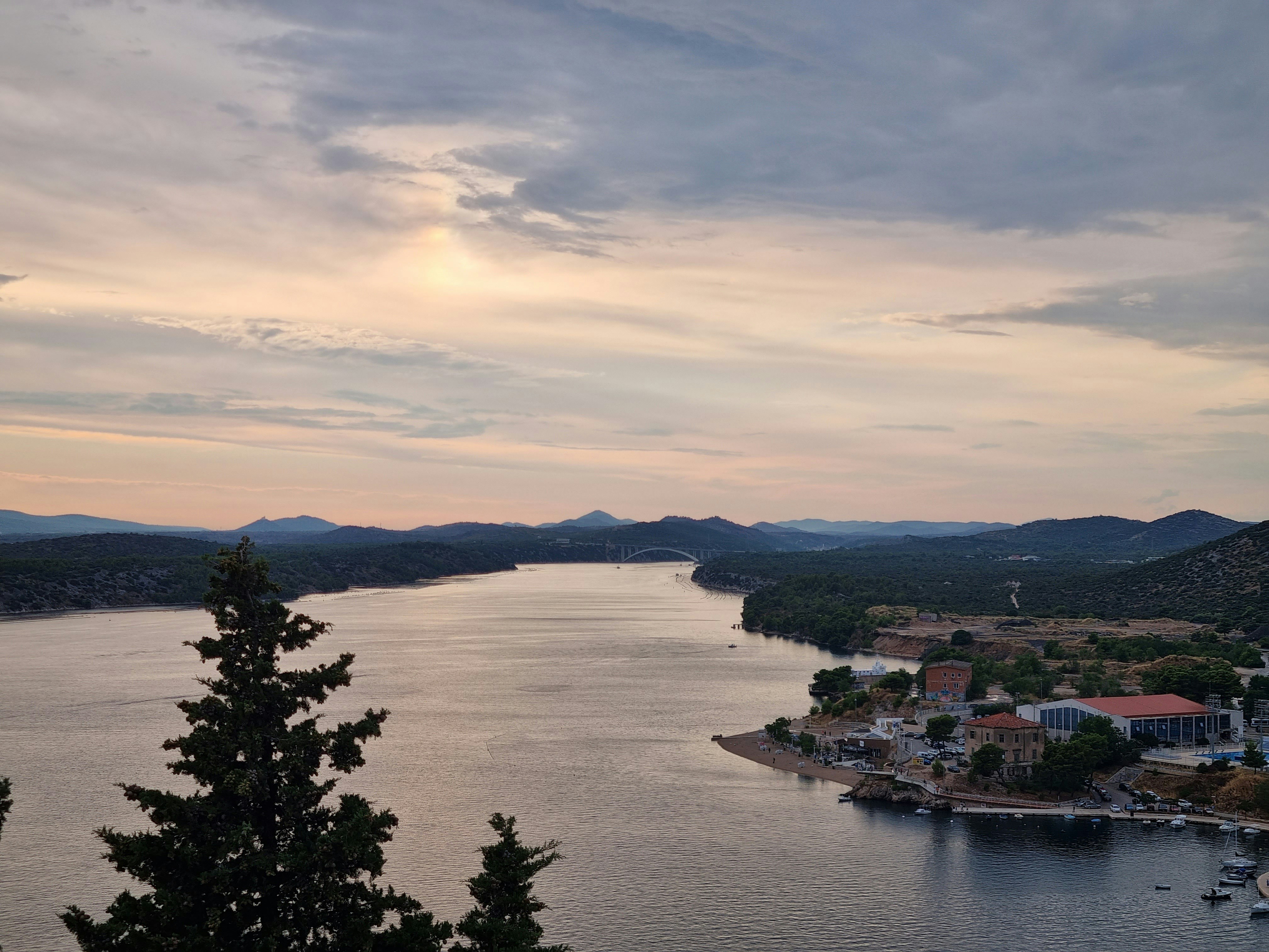 Sunset Bend over the Quiet River: Pines Framing a Lakeside Village