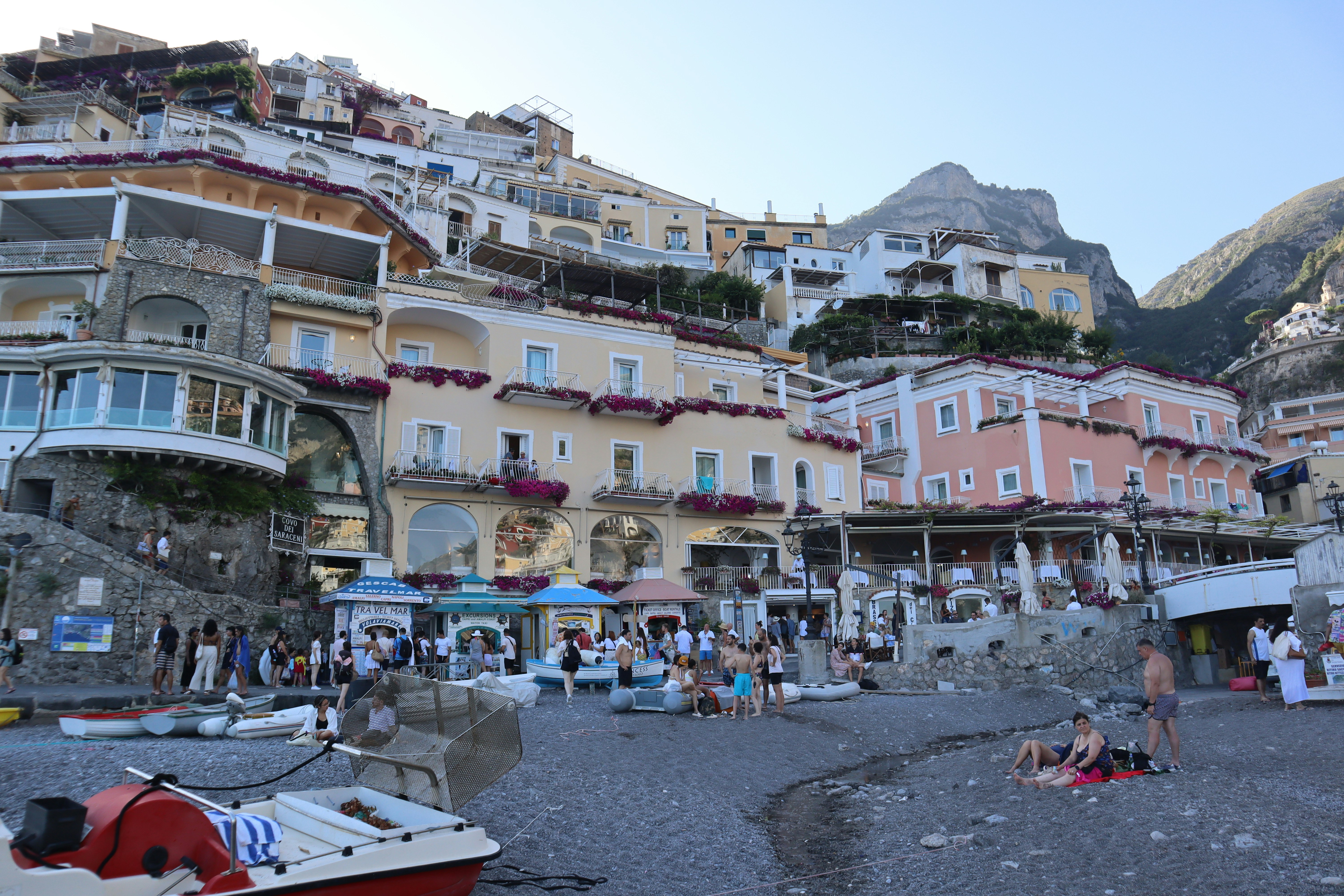 Cliffside pastel village rising above a sunlit pebble beach
