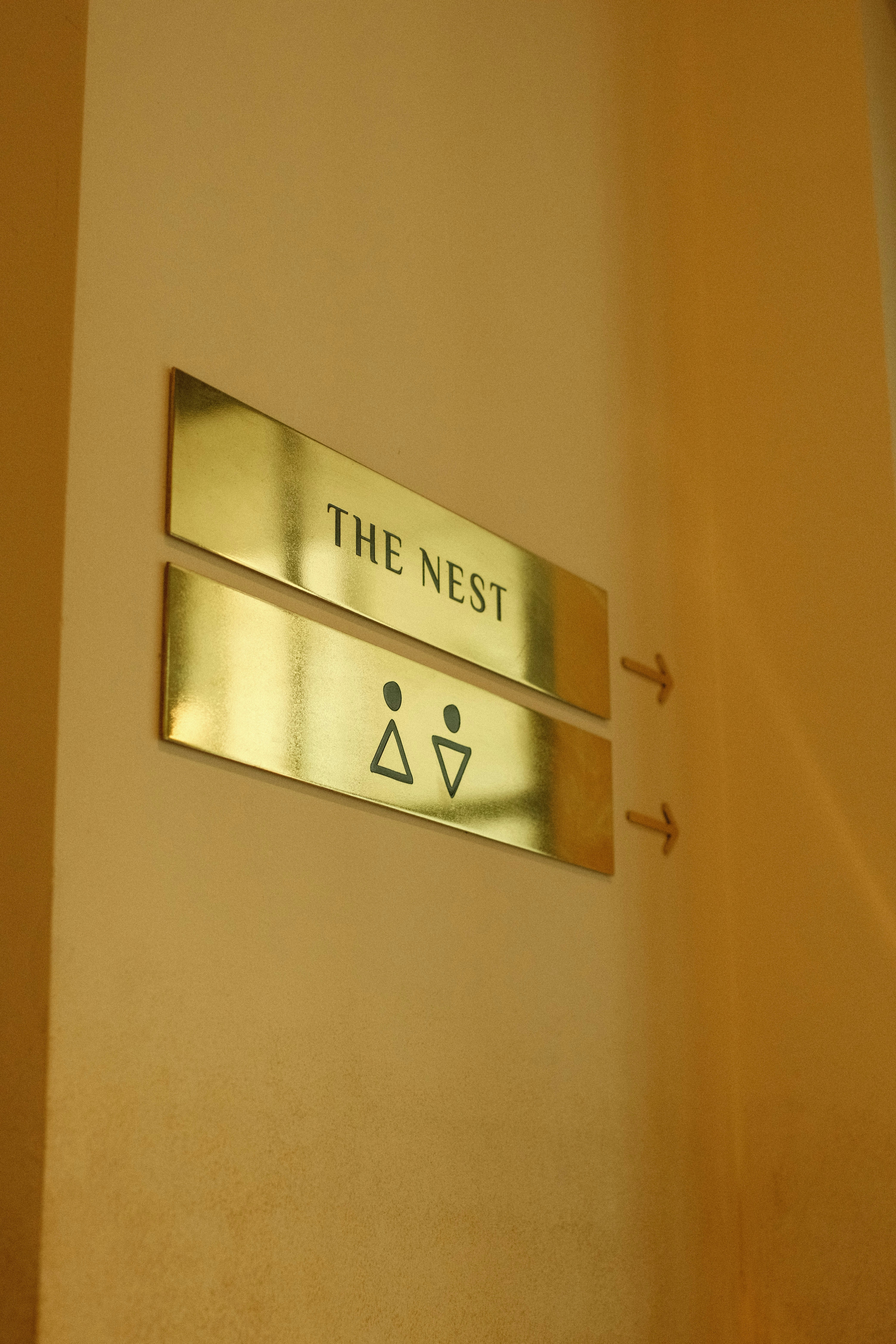 Amber-lit Brass Sign 'THE NEST' in a Quiet Corridor