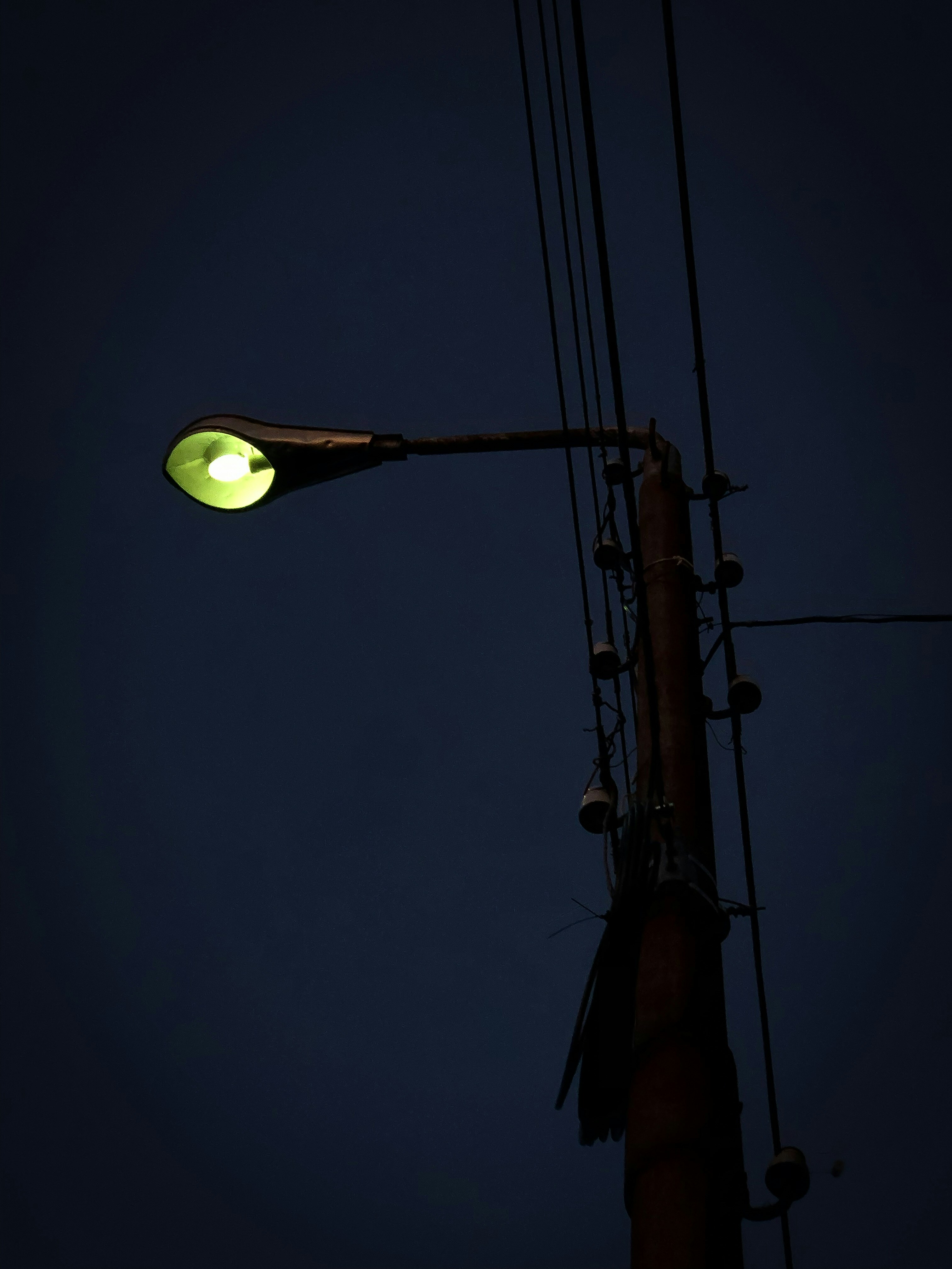 Emerald Glow Between Wires: A Night Streetlamp in Deep Blue