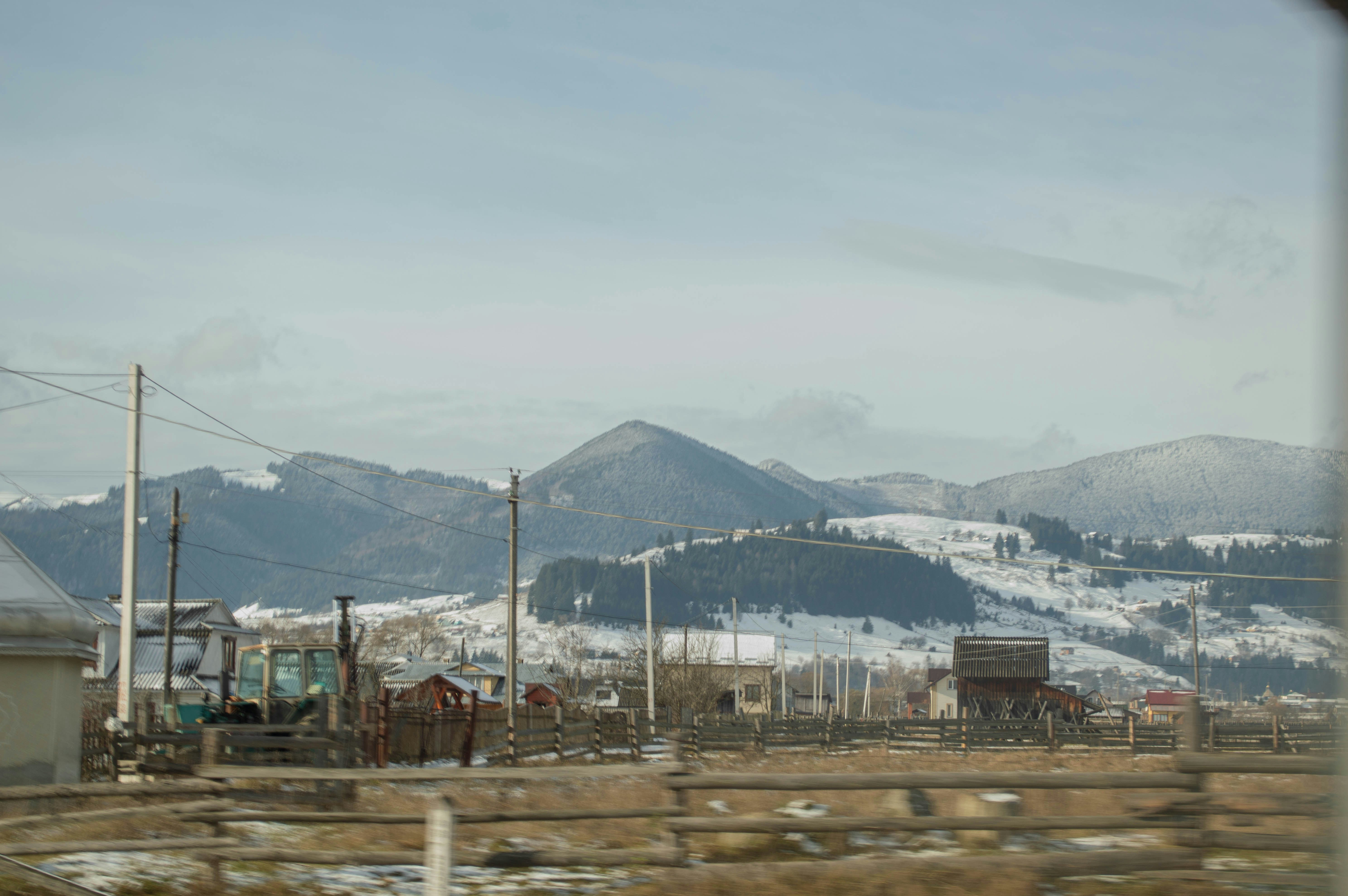 Snow-Dusted Peaks Over a Quiet Farmyard Horizon