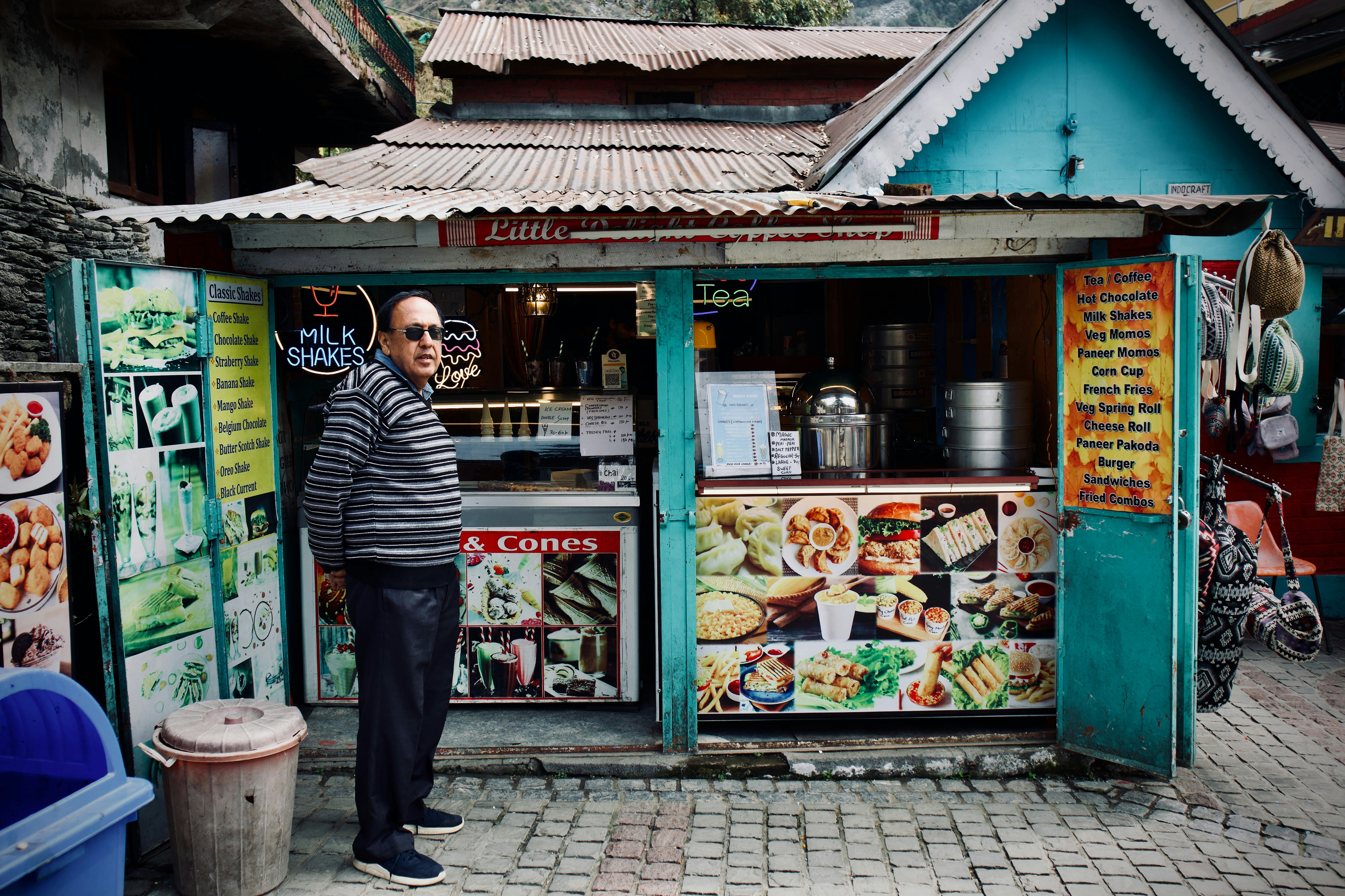 A man standing in front of a food stand photo – Free Triund Image on ...