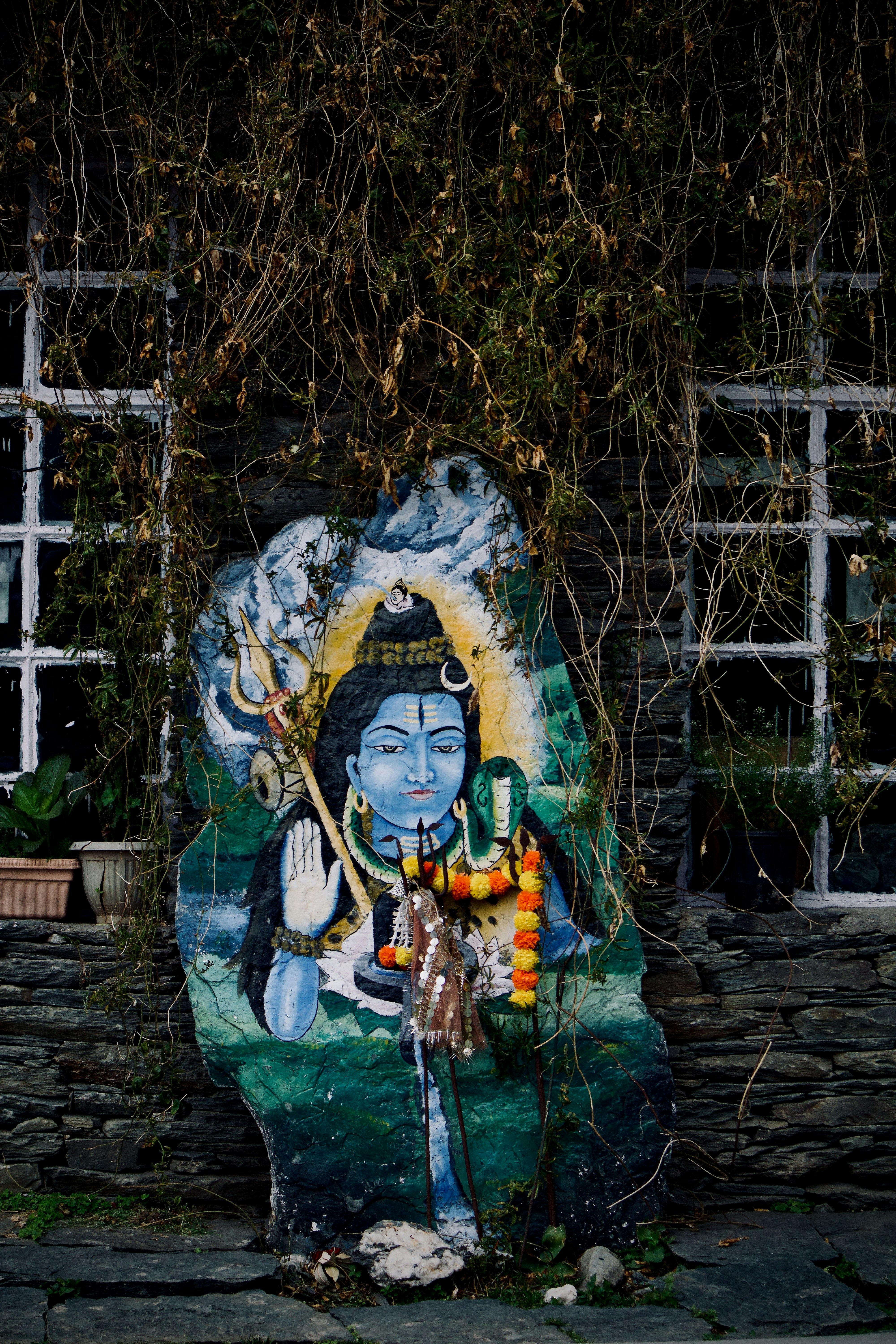 Ivy-Guarded Blue Deity: A Painted Stone Relief Framed by Vines