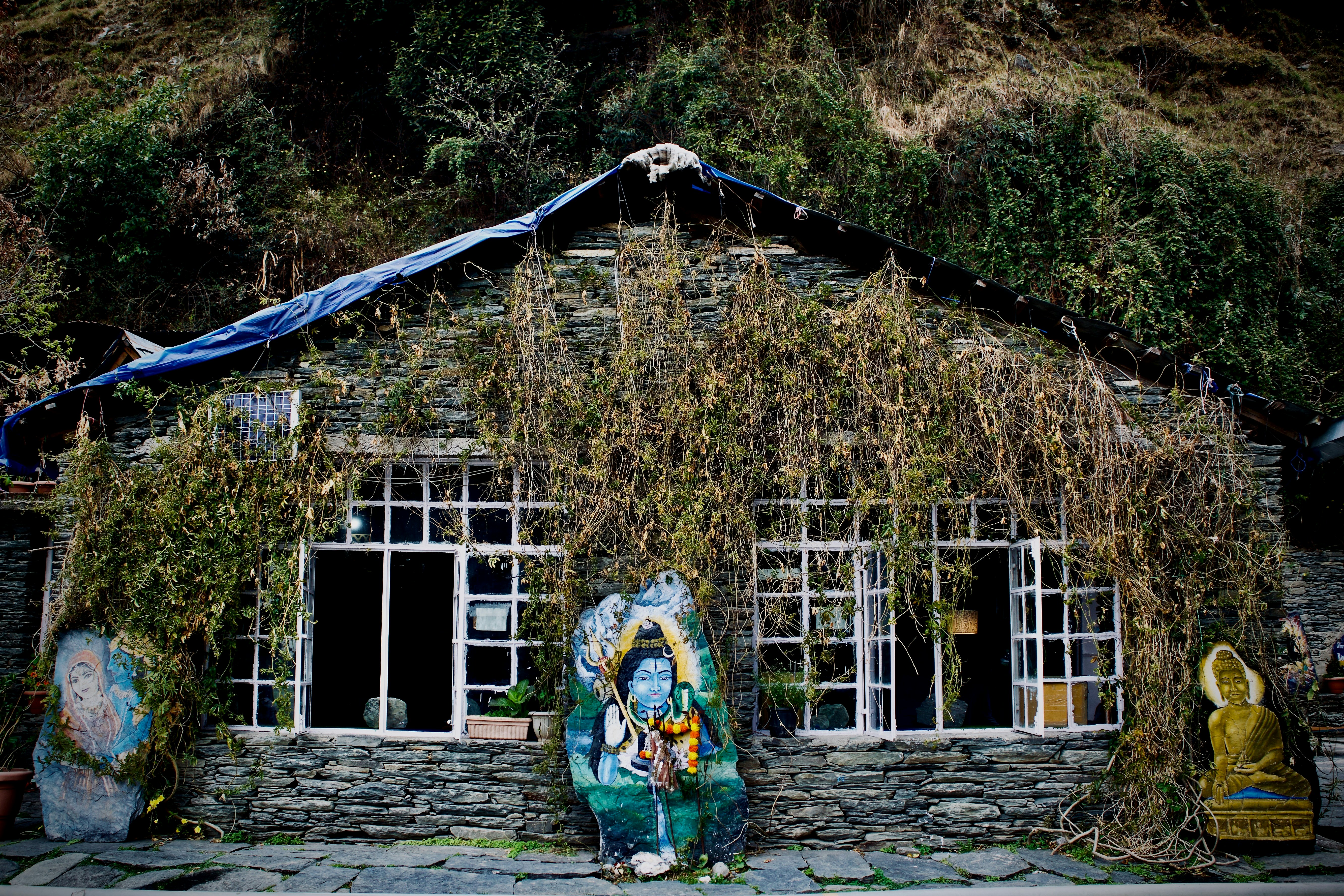 Stone building covered in ivy with colorful statues at the entrance.