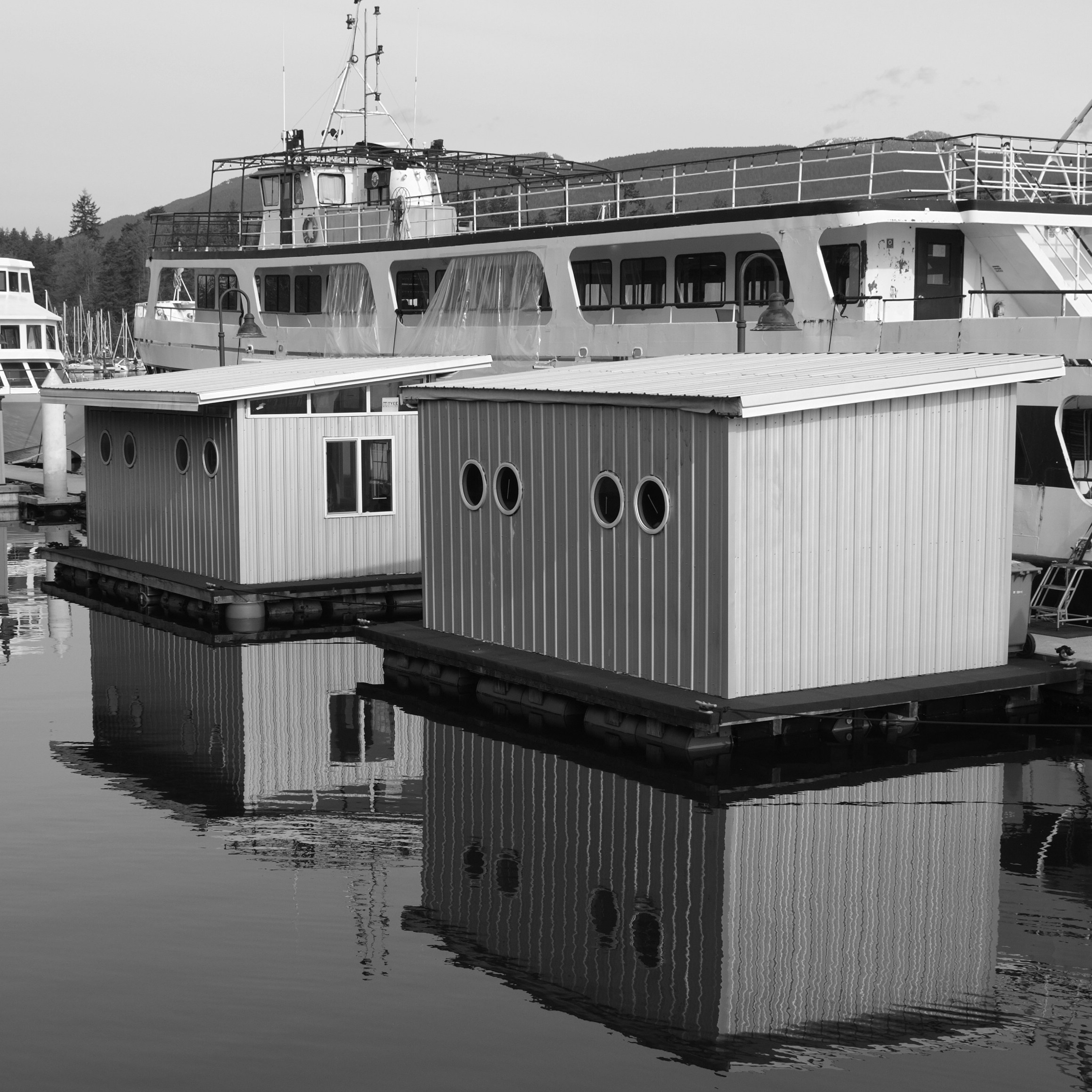 Two Floating Cabins, One Quiet Marina: Vertical Siding and Glass Reflections