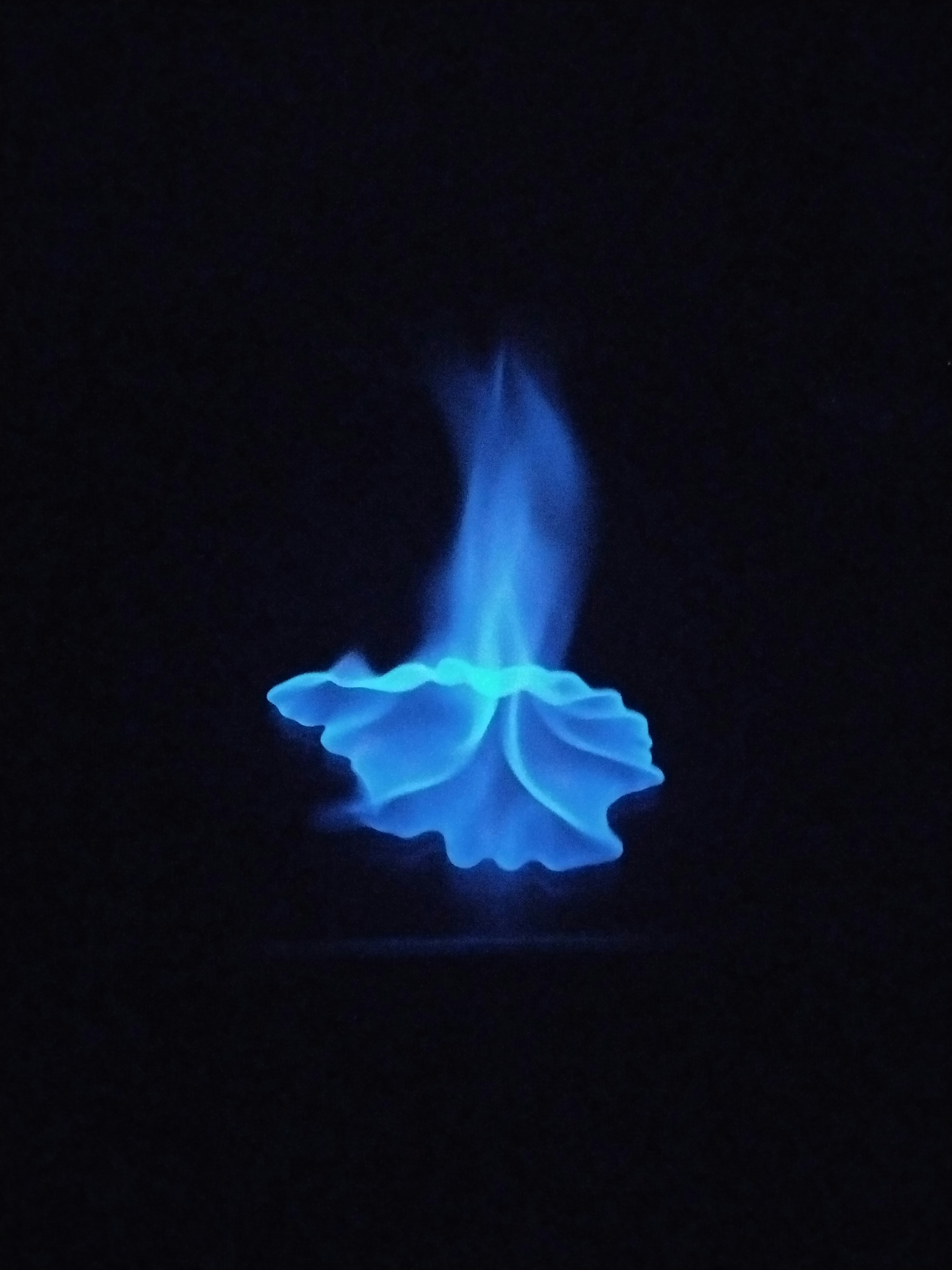 A mesmerizing blue flame flickers against a dark backdrop, showcasing intricate shapes and movements. The image captures the fluidity and elegance of fire.