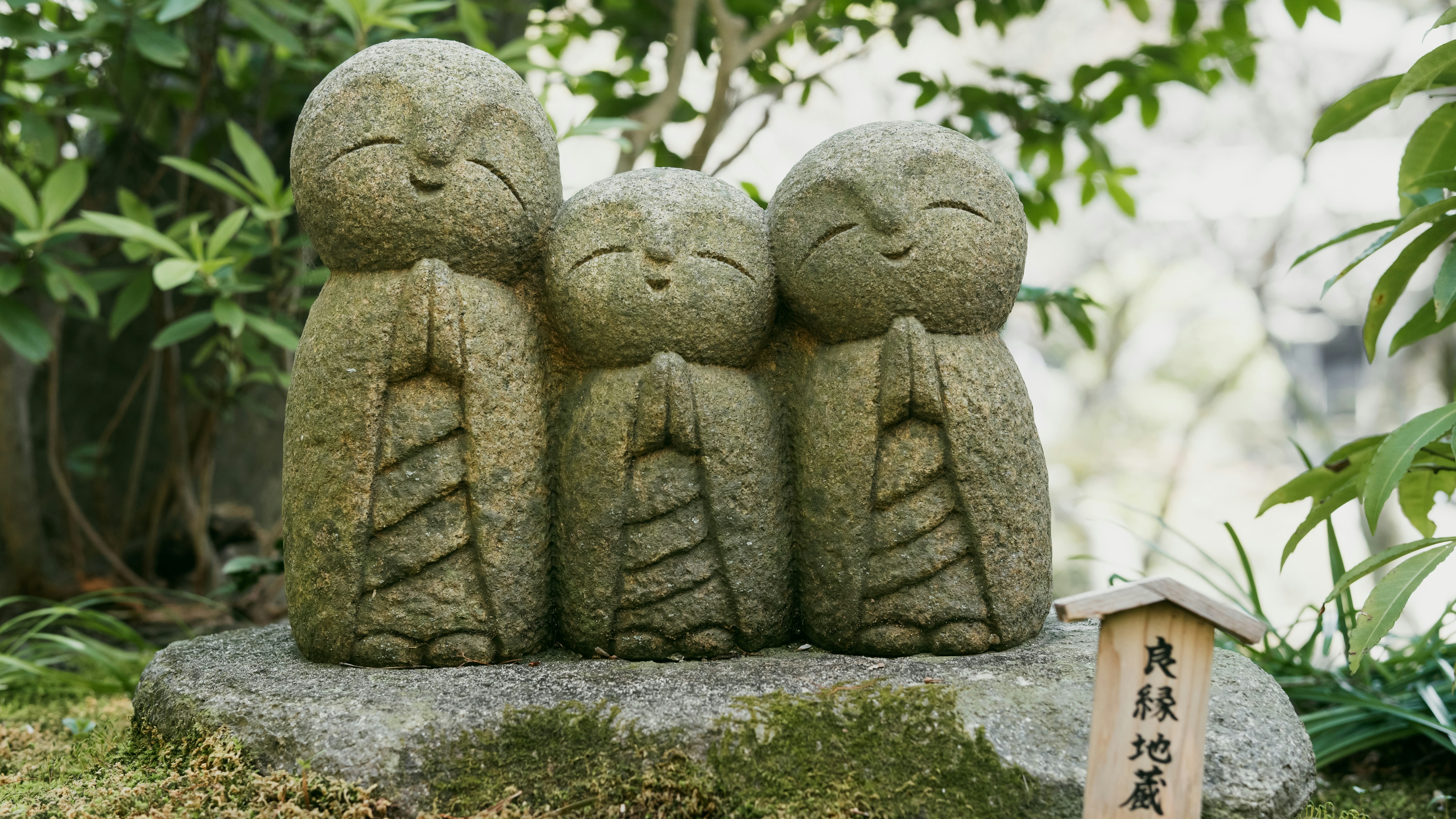 A group of stone statues sitting on top of a lush green field photo ...