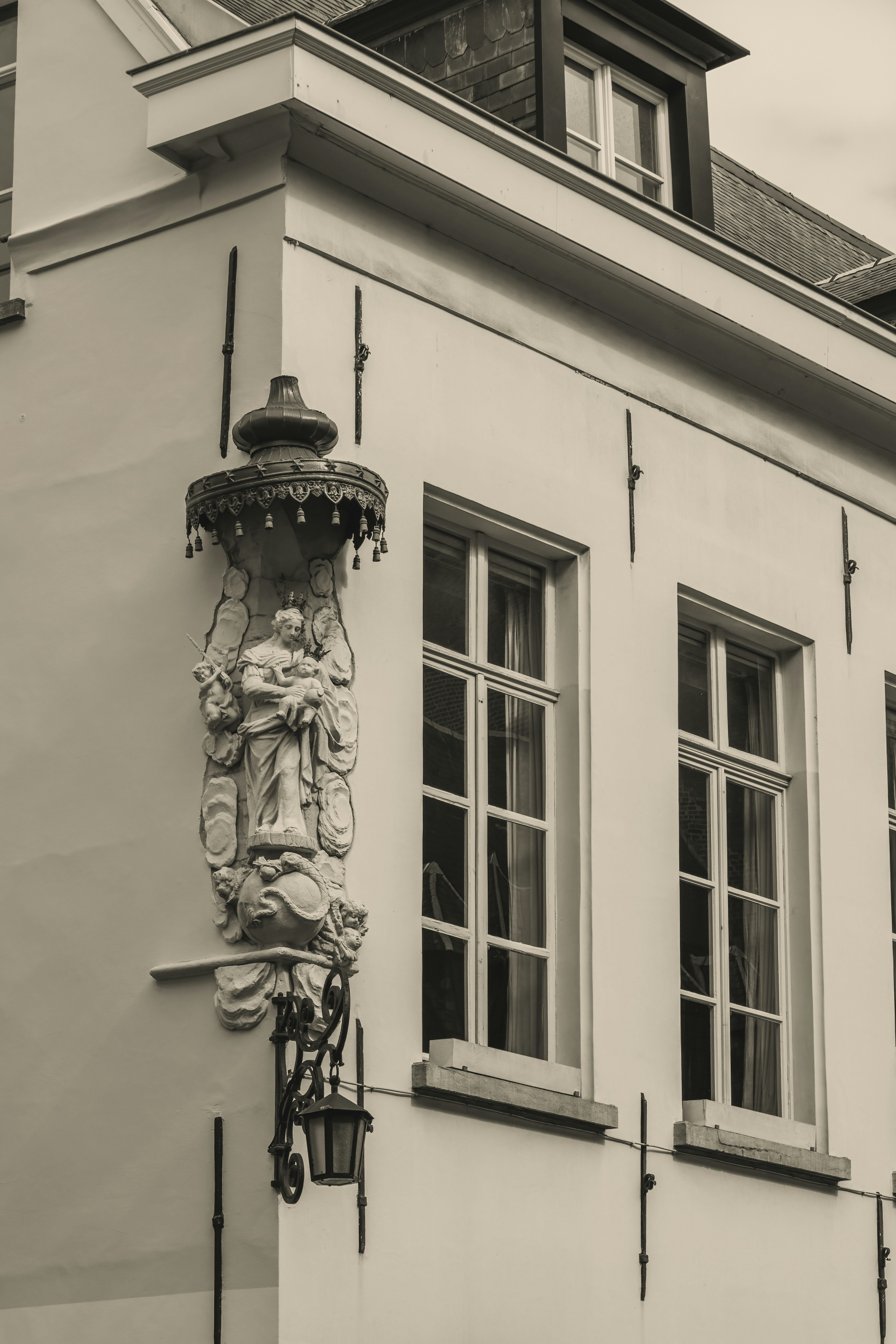 Guardians in Stone: Baroque Relief Framing a Lantern on a Townhouse