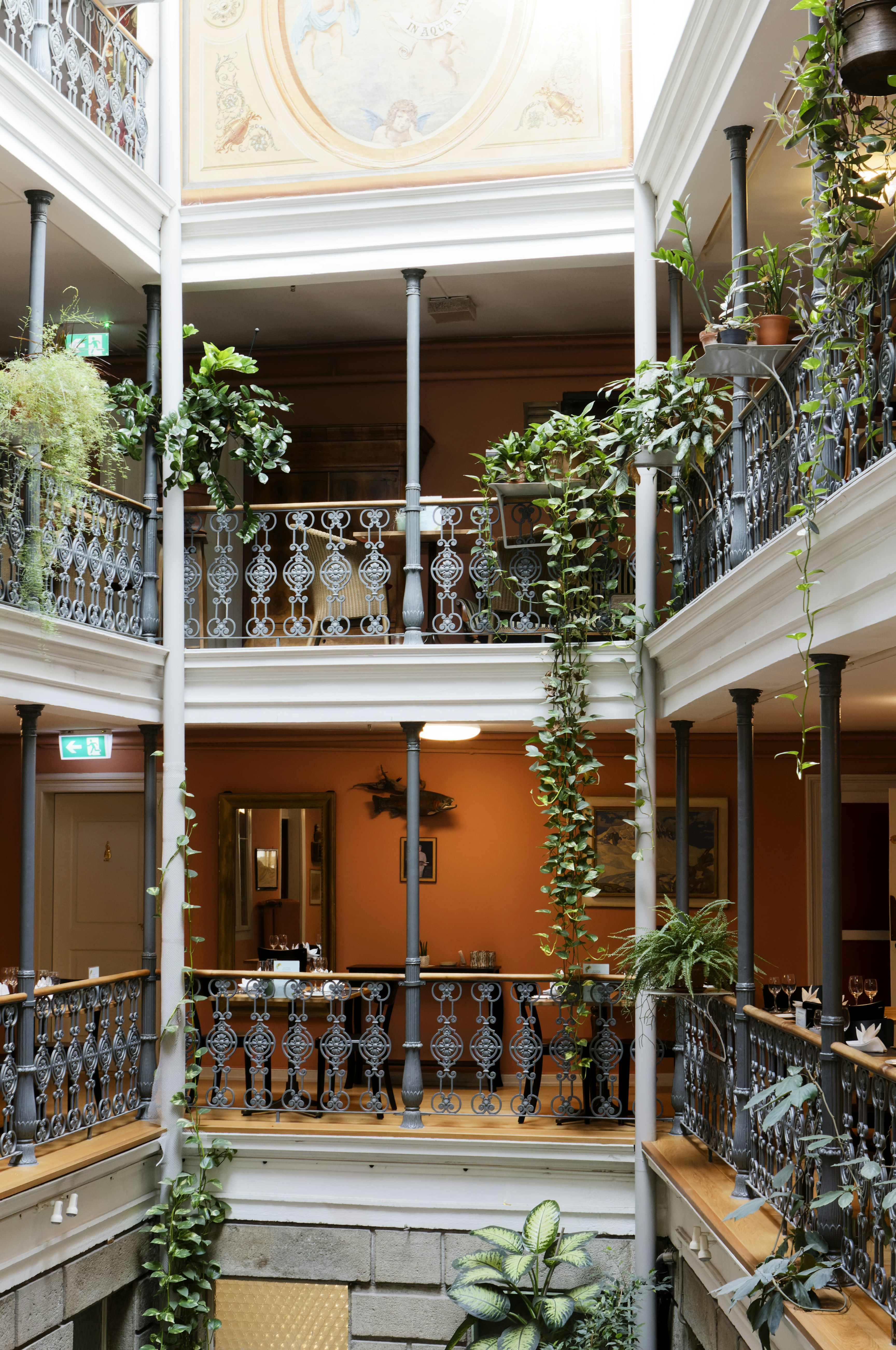 Verdant Balconies in an Atrium: Ironwork, Light, and Lush Greenery