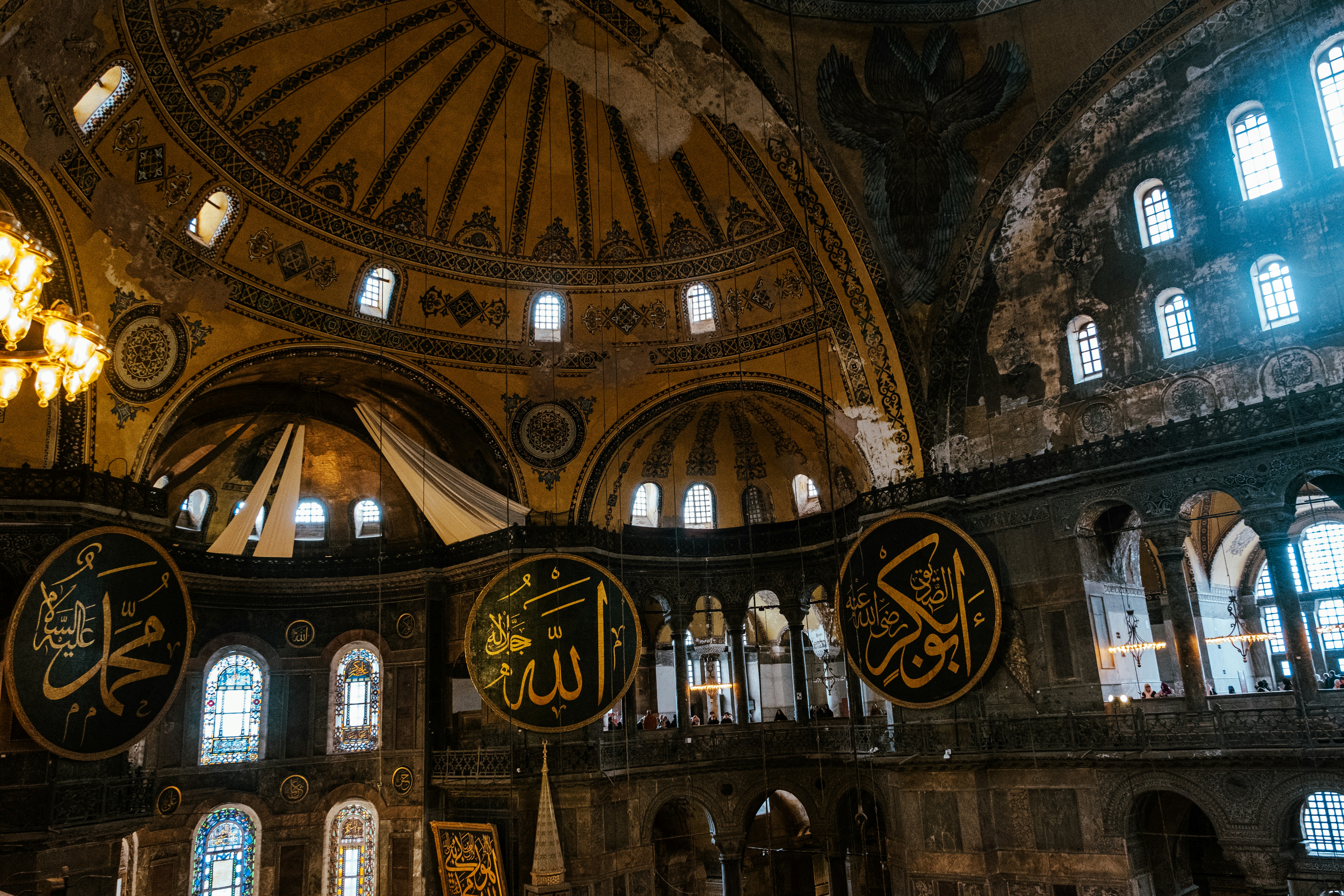 Intricate interior of Hagia Sophia showcasing grand domes and ornate decorations, highlighted by large circular calligraphy panels.