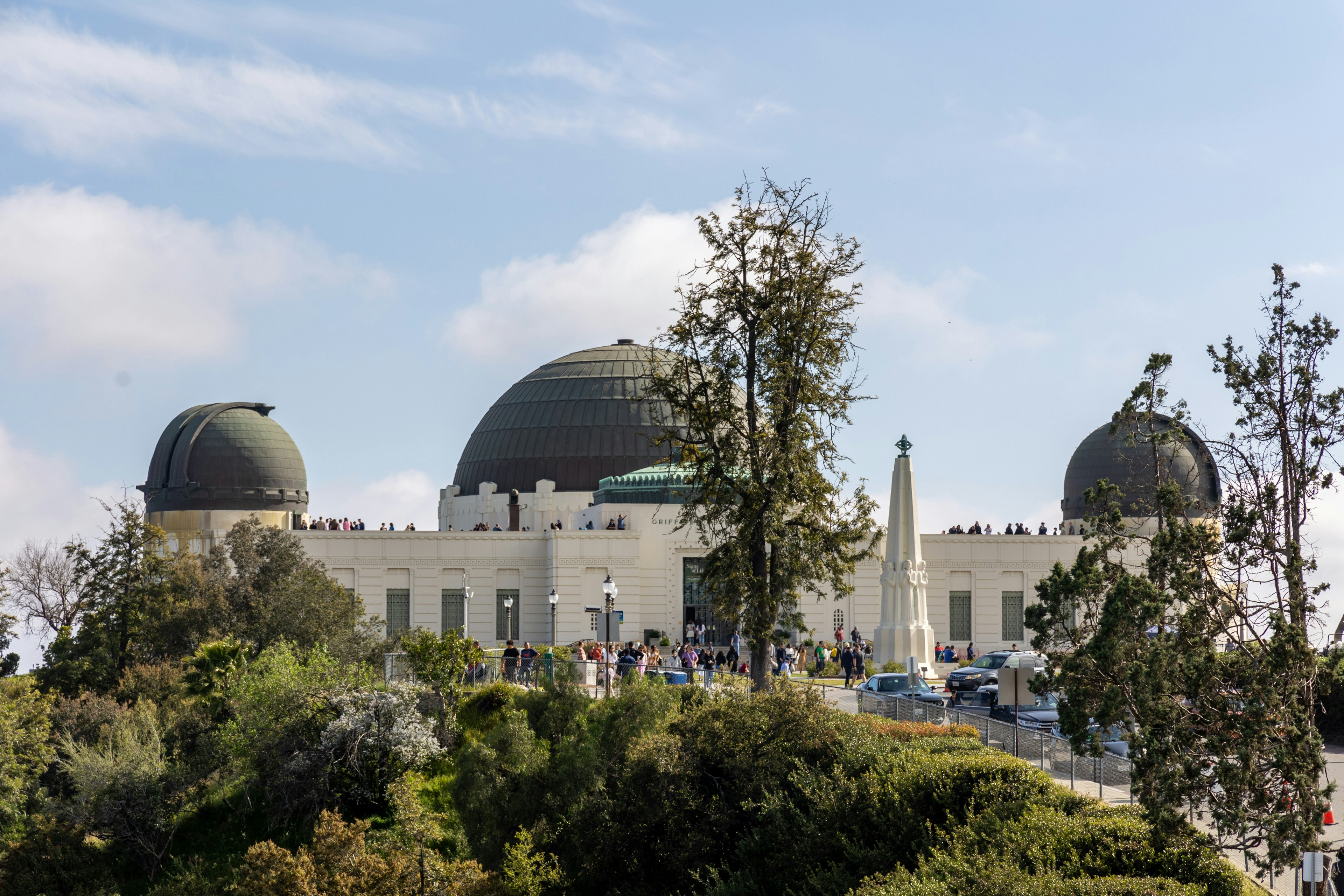 Griffith Observatory surrounded by lush greenery under a clear blue sky.