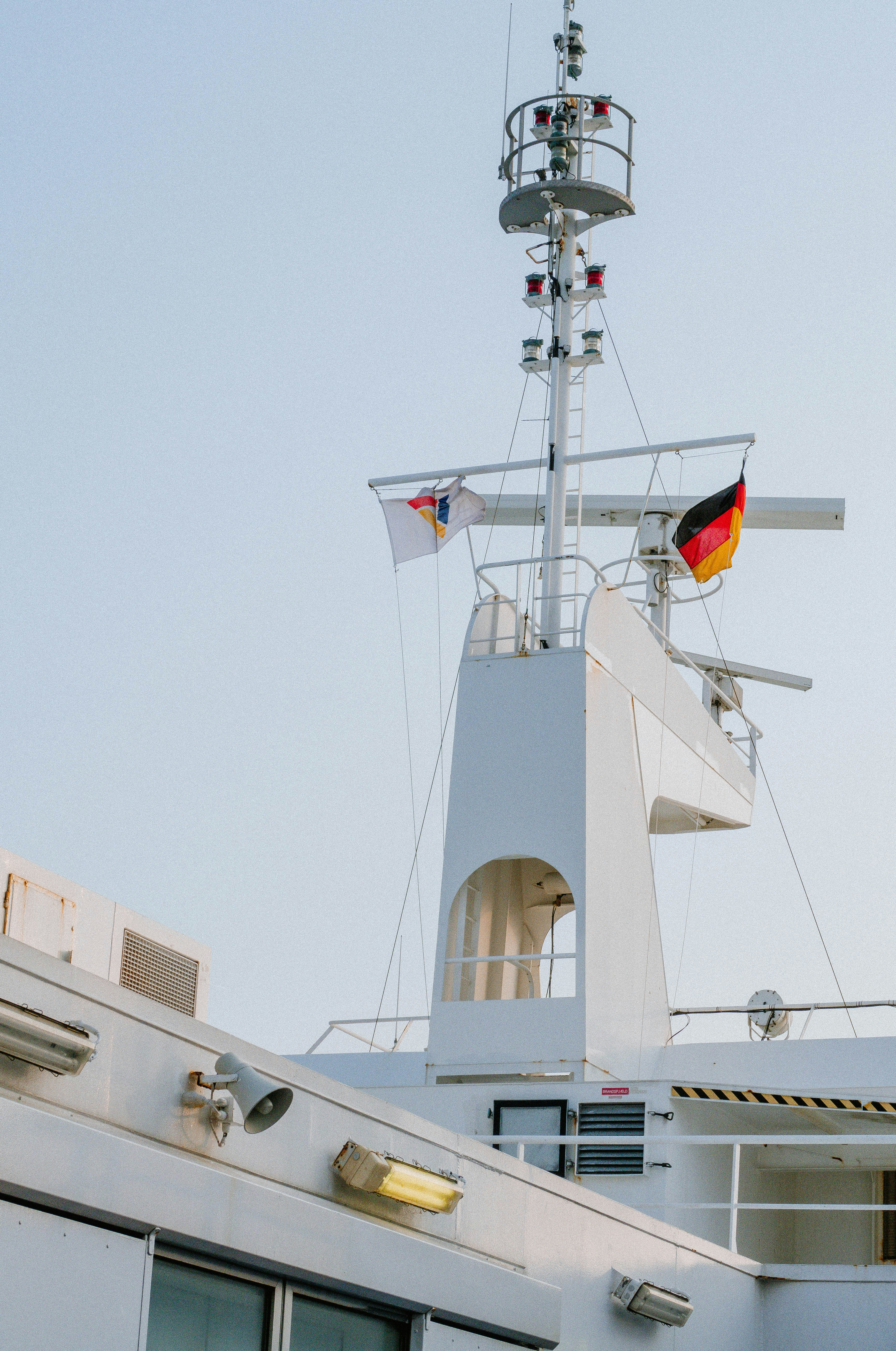 German Flag at the Mast: A White Vessel Crowned by Antennas Against a Pale Sky