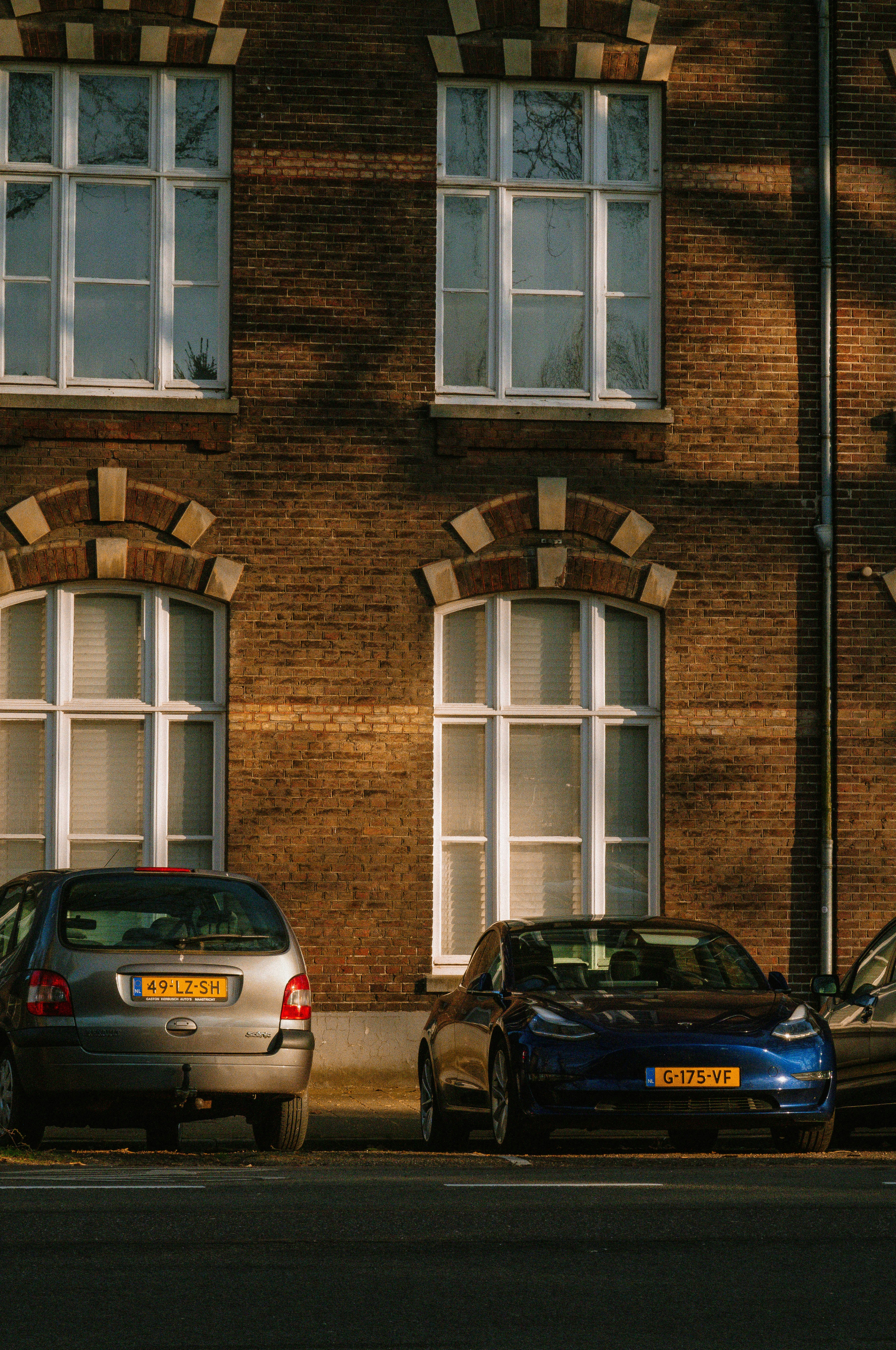 Golden Hour on a Brick Street: A Pair of Cars Framed by Arched Windows