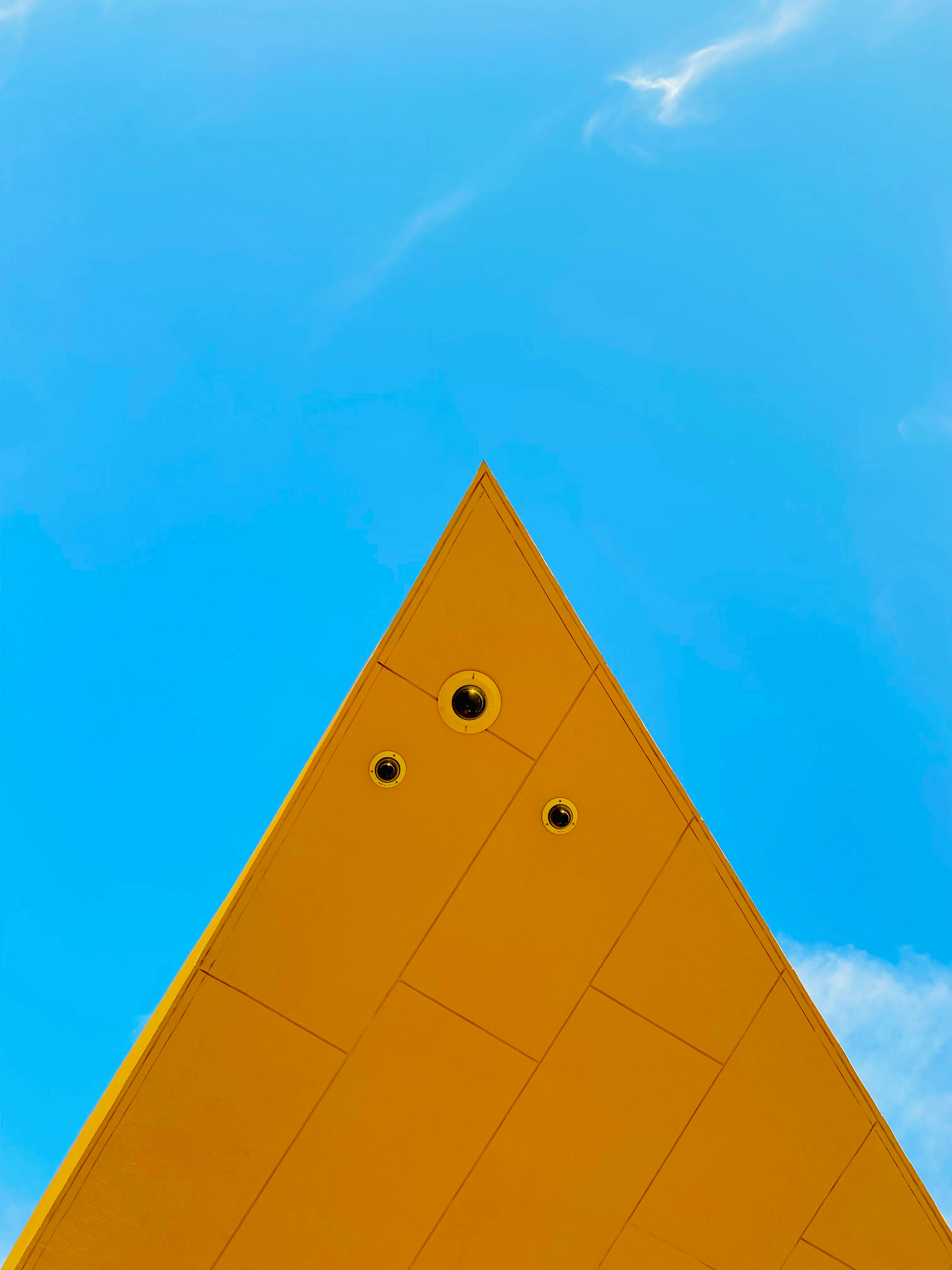 A yellow triangle with holes in the middle of it photo – Free Blue ...