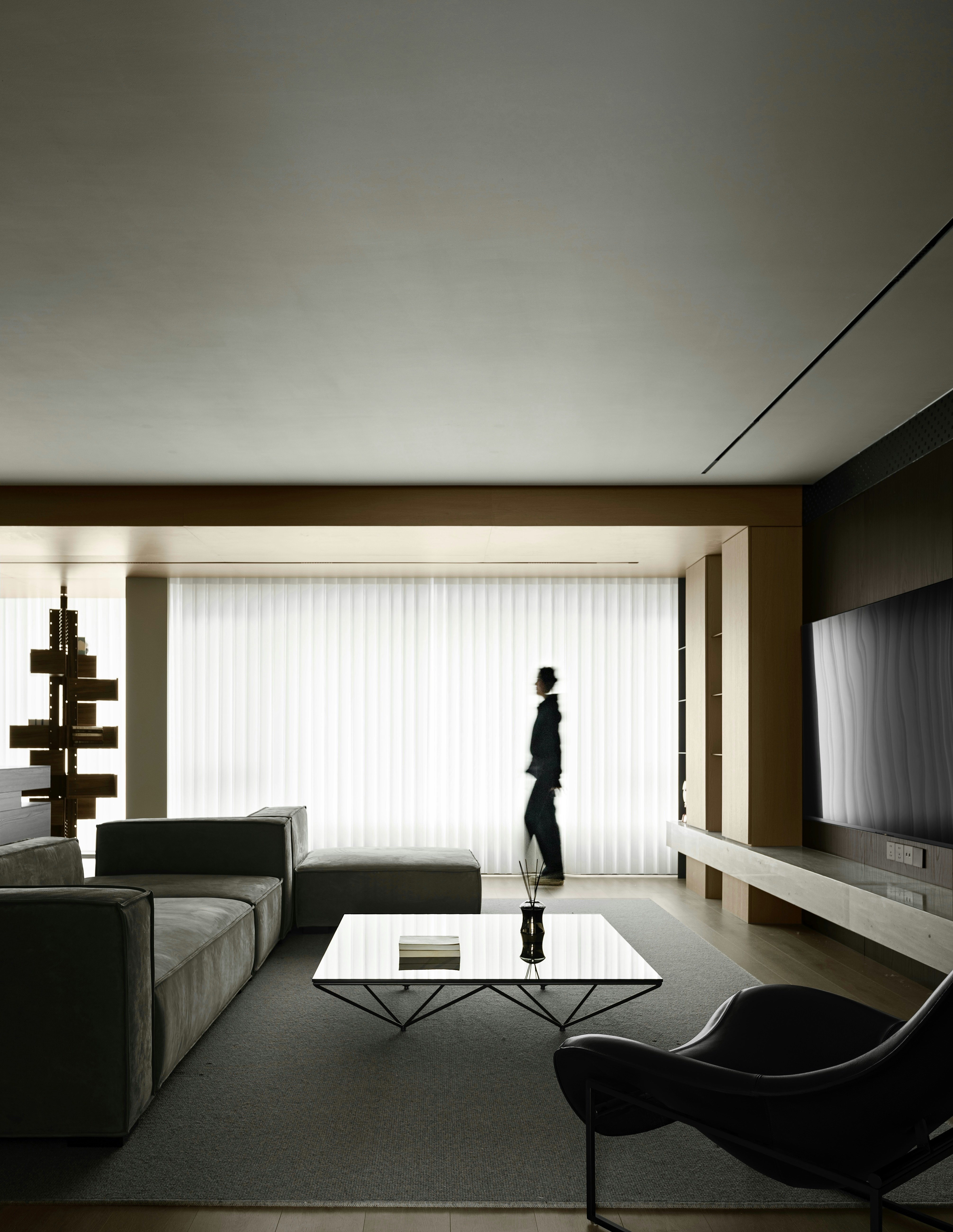 Silhouette in a Sunlit Loft: A Figure Glides Past Vertical Blinds