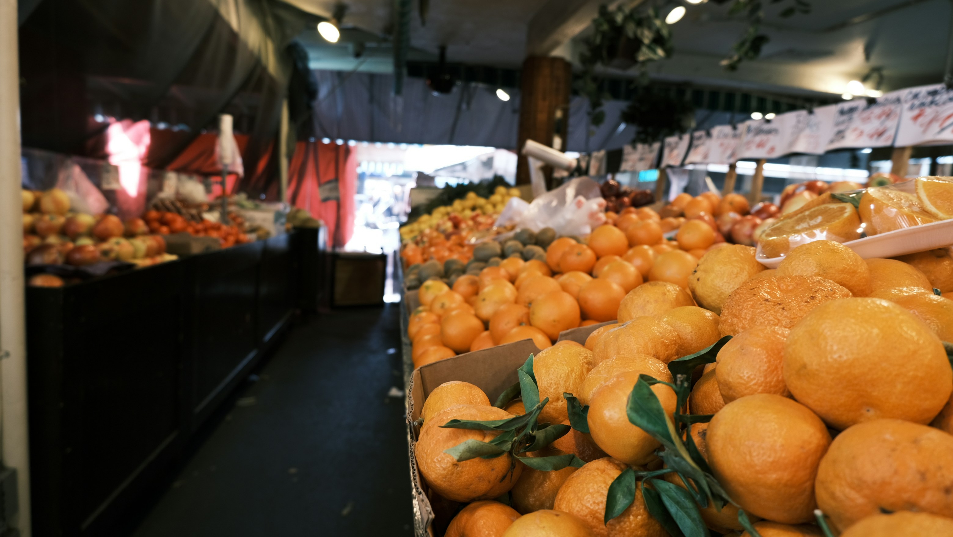 Citrus Glow at the Market: Oranges Framing a Dim Aisle