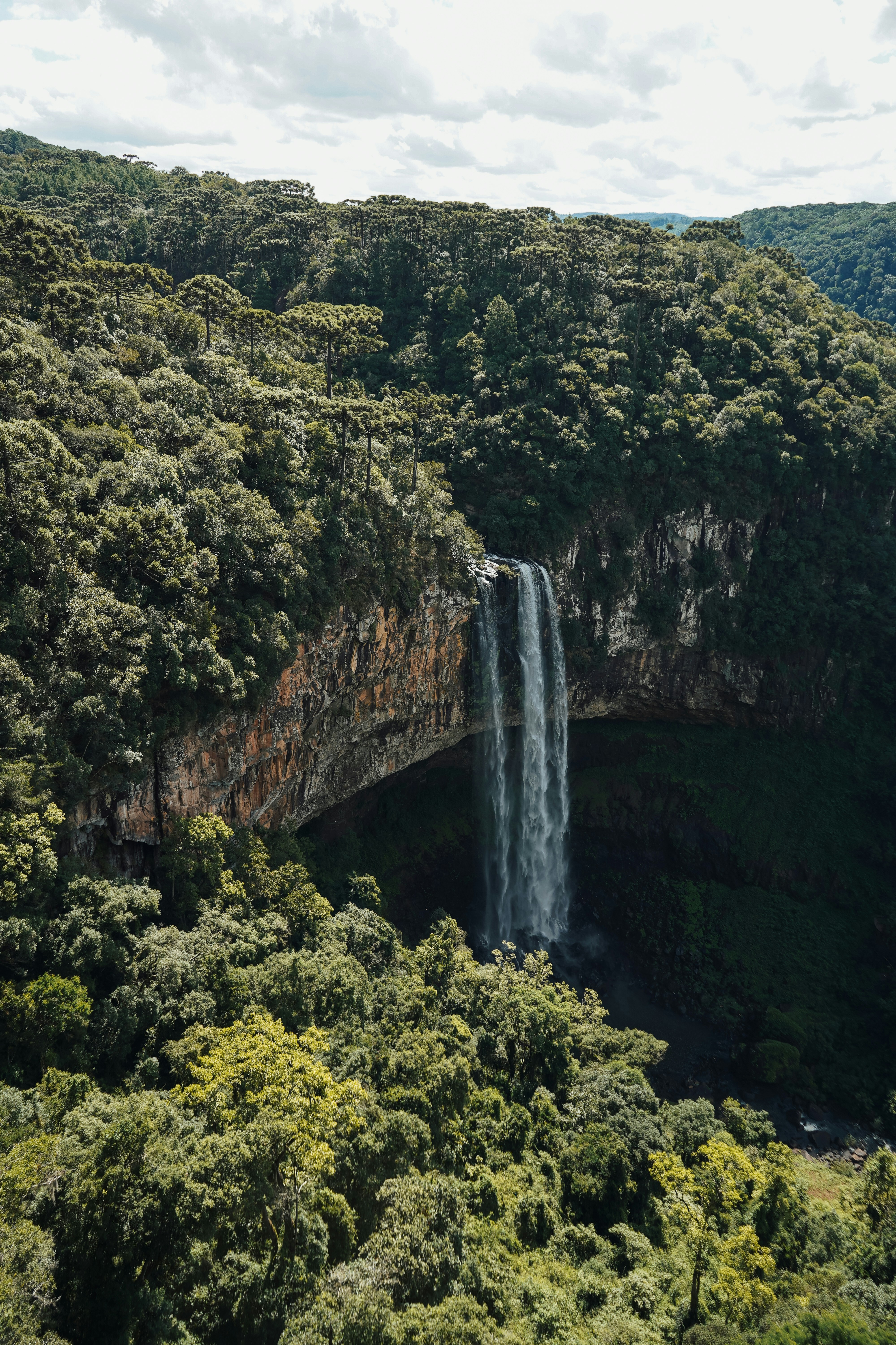 Tall waterfall plunging down a steep cliff surrounded by lush forest.