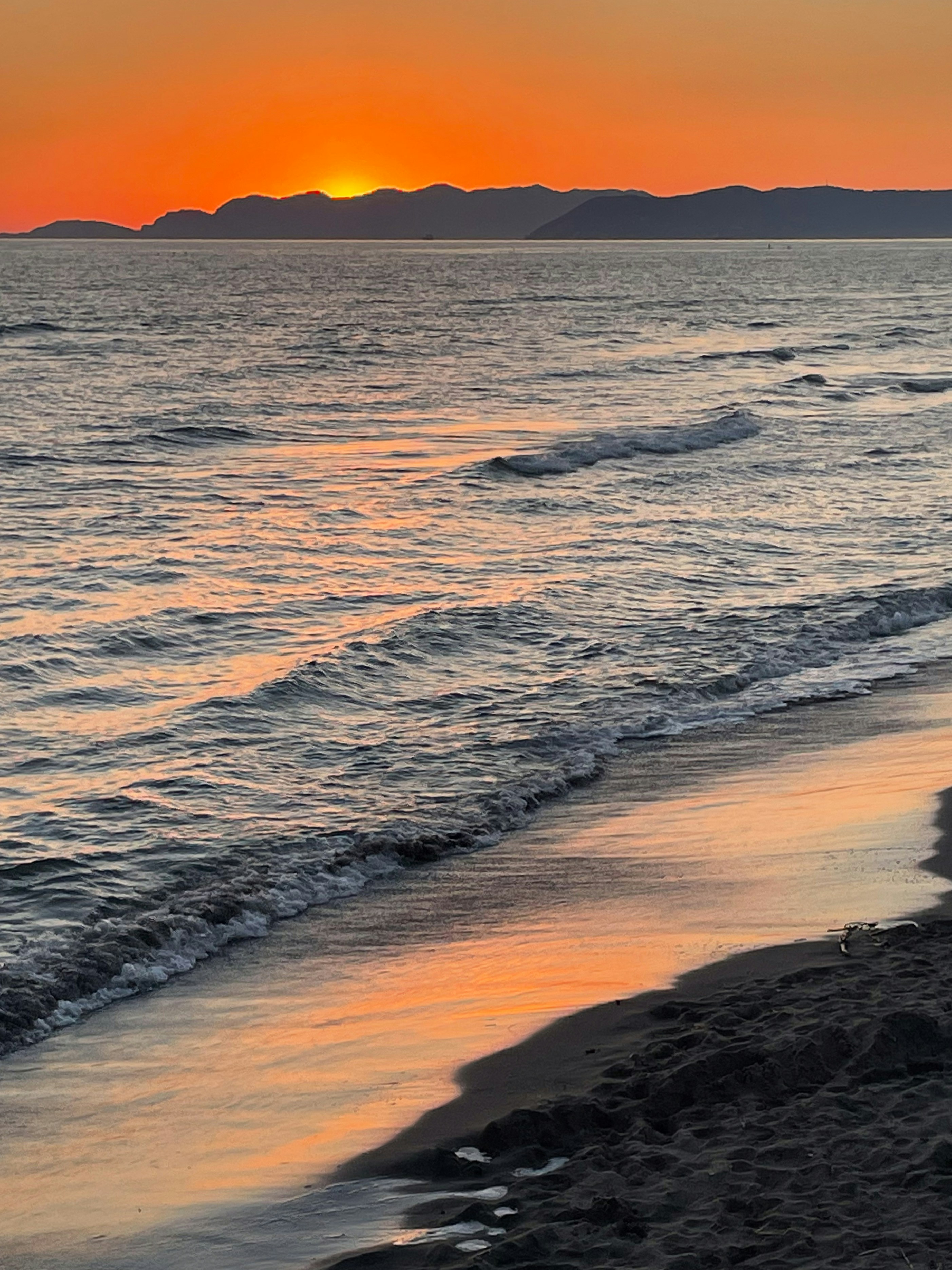 Sunrise Ember over the Velvet Shore: Distant Peaks and Reflective Surf